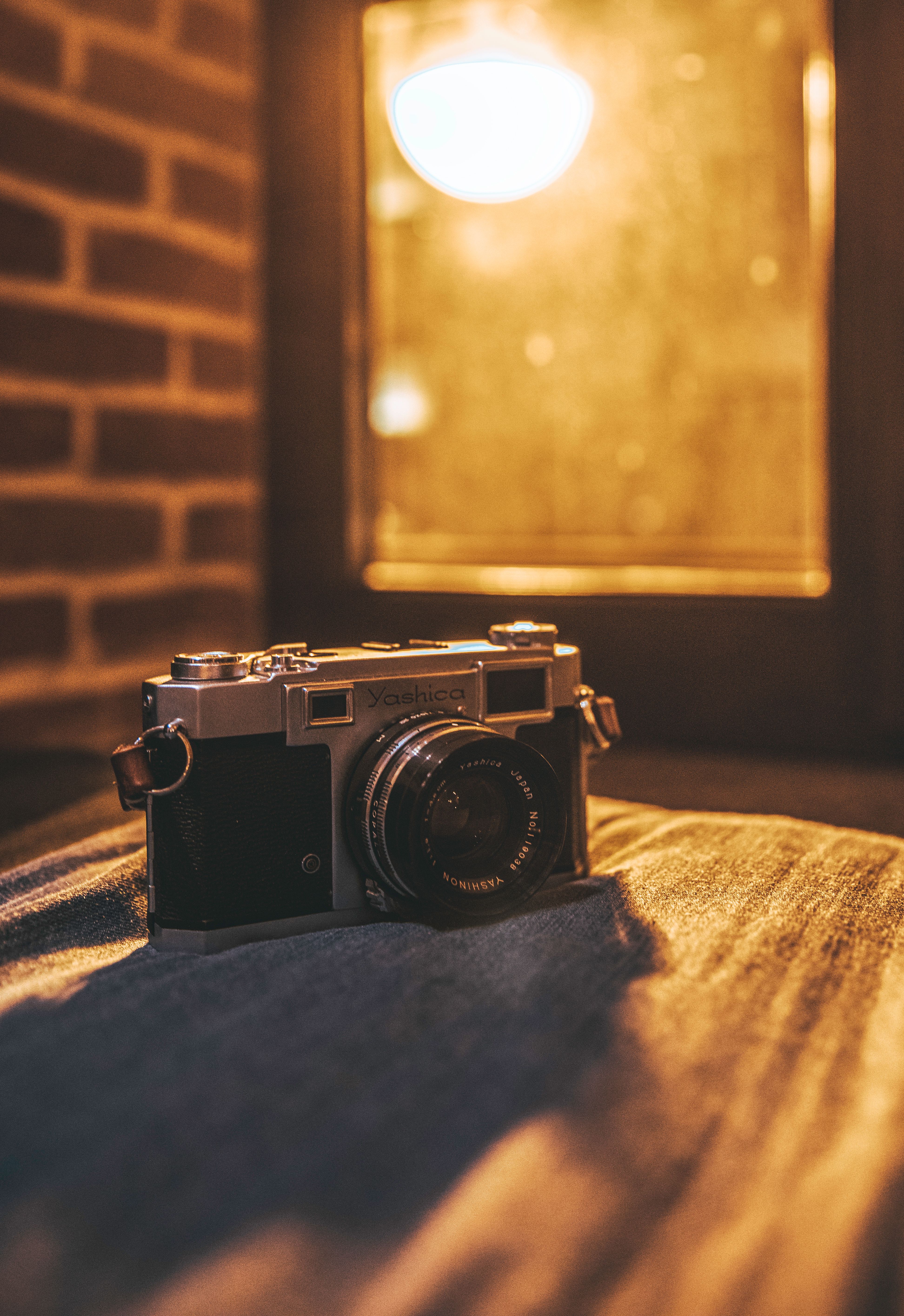 An old camera sitting on a table in front of a window · Free Stock Photo