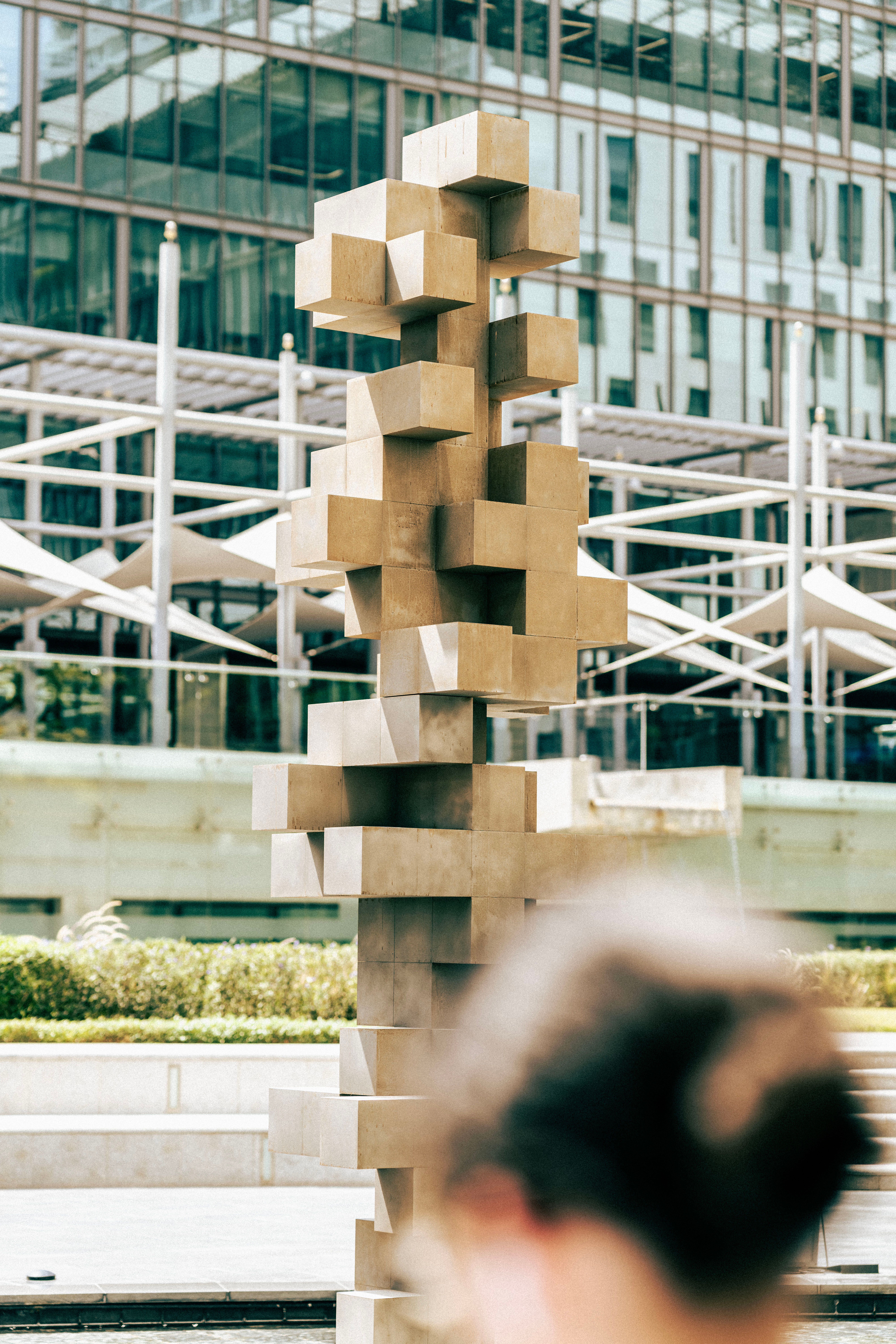 A woman is walking by a sculpture of cubes · Free Stock Photo