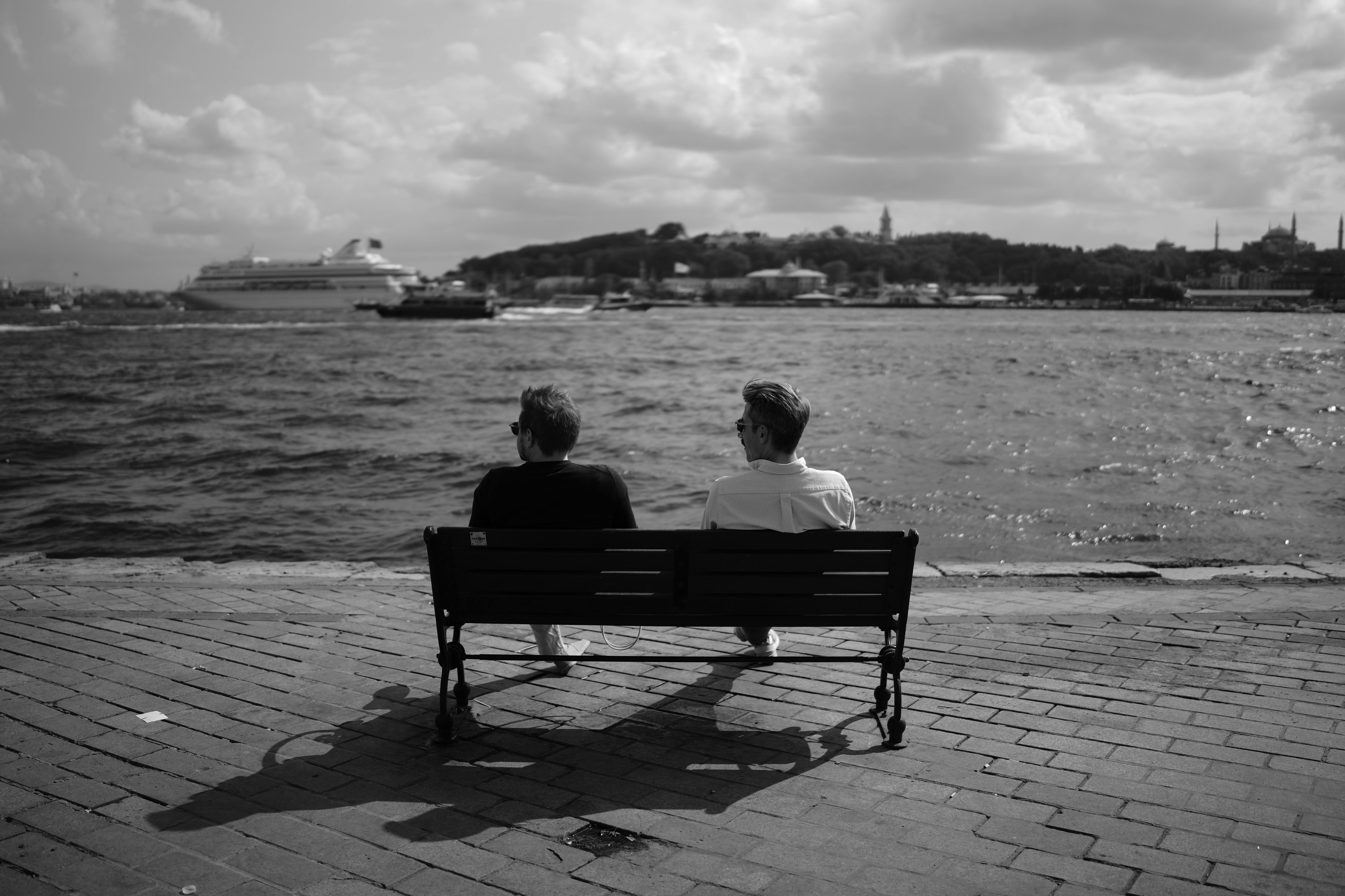 Grayscale Photo of Two Person Sitting on a Bench · Free Stock Photo