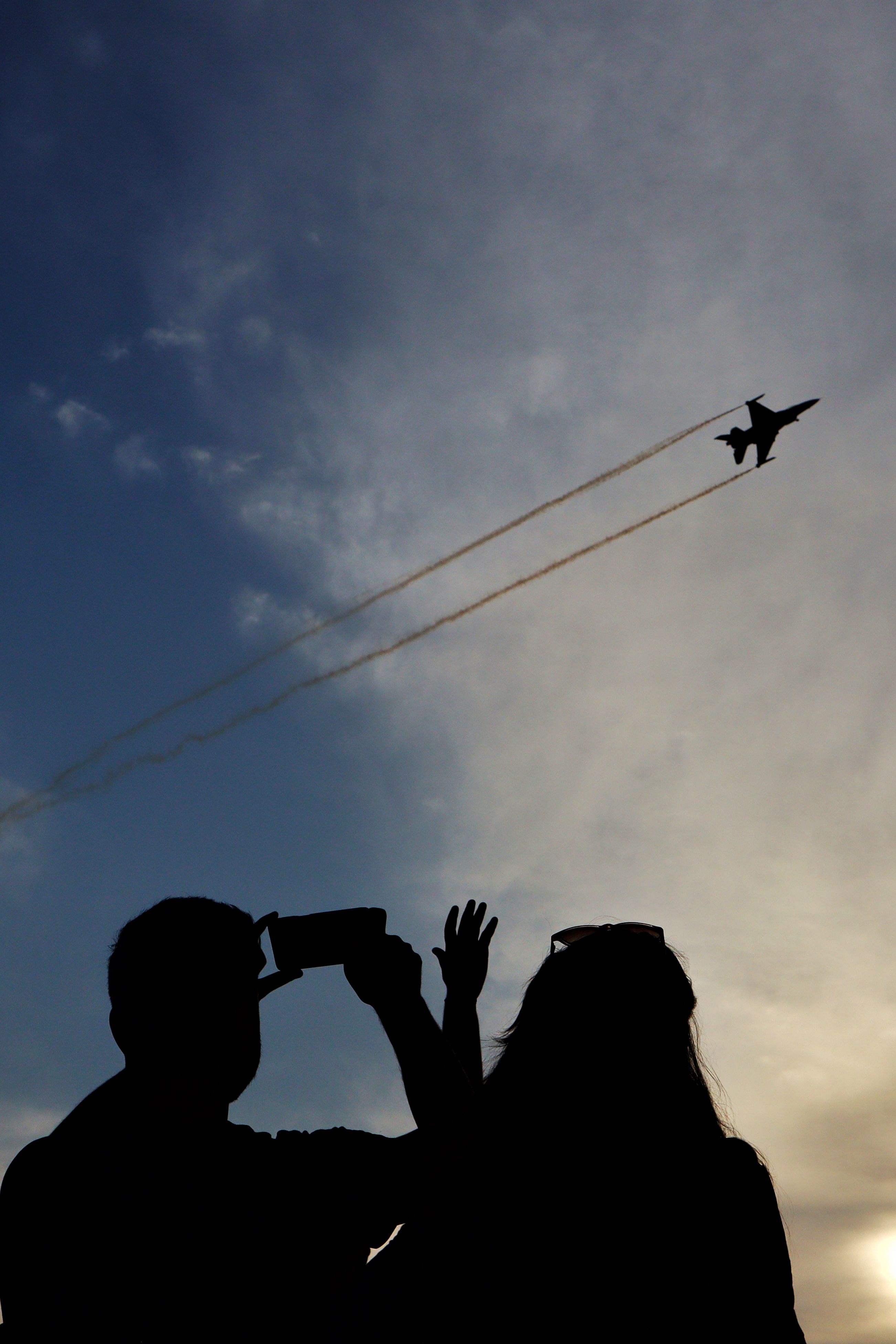 Silhouettes of Spectators Filming a Jet at an Air Show · Free Stock Photo