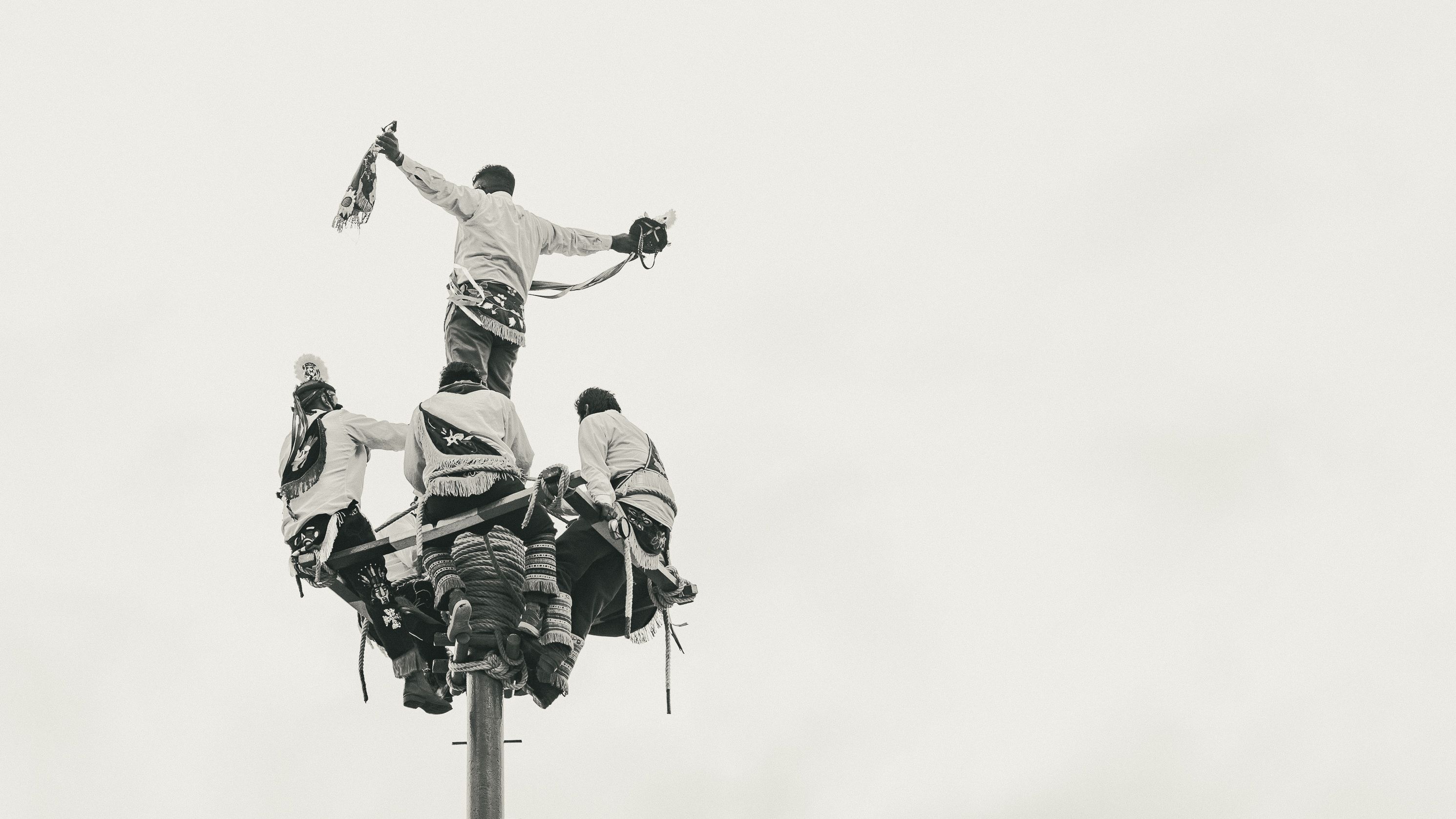 Men Standing and Sitting on Pole at Festival · Free Stock Photo