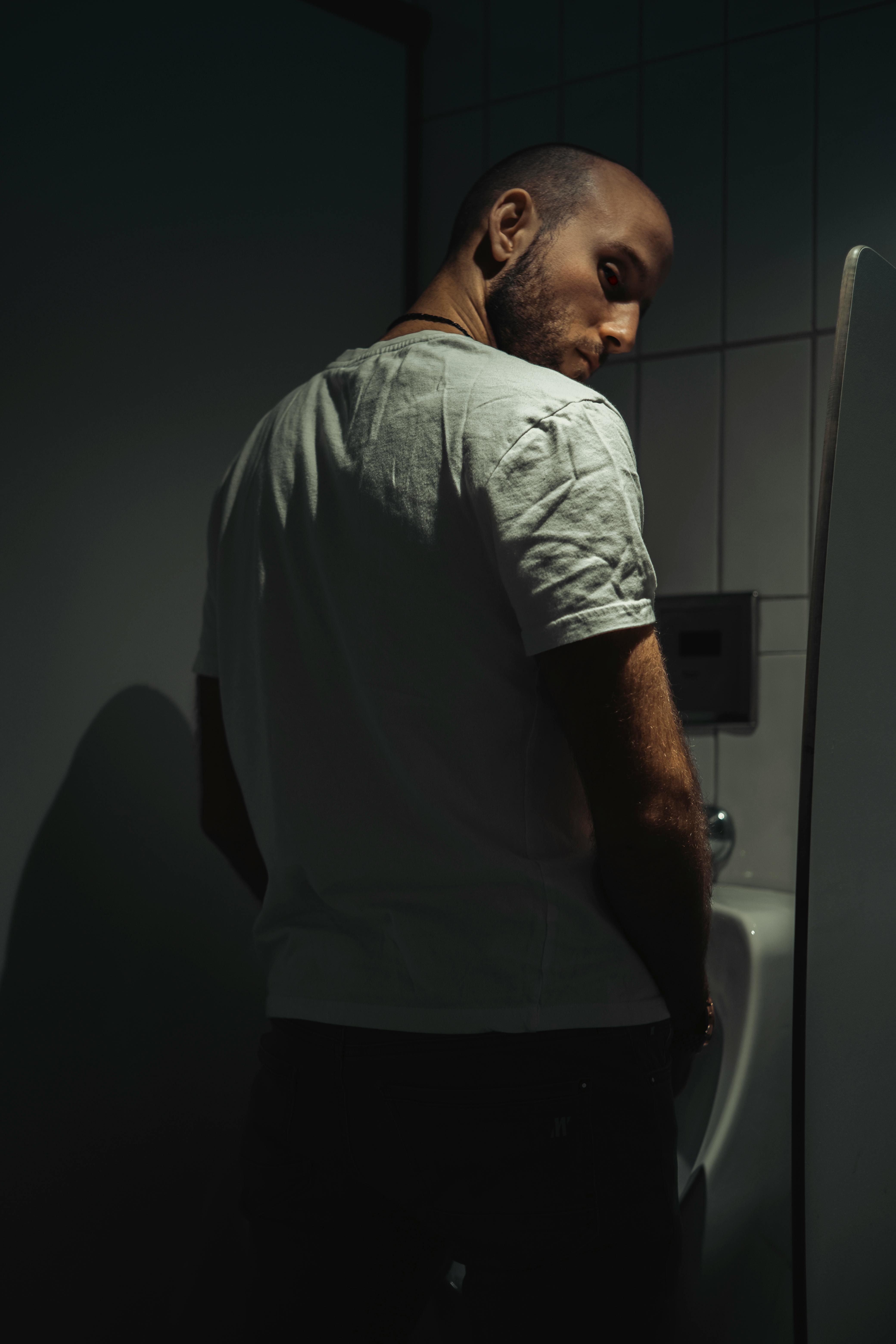 Man Standing at the Urinal in the Bathroom · Free Stock Photo