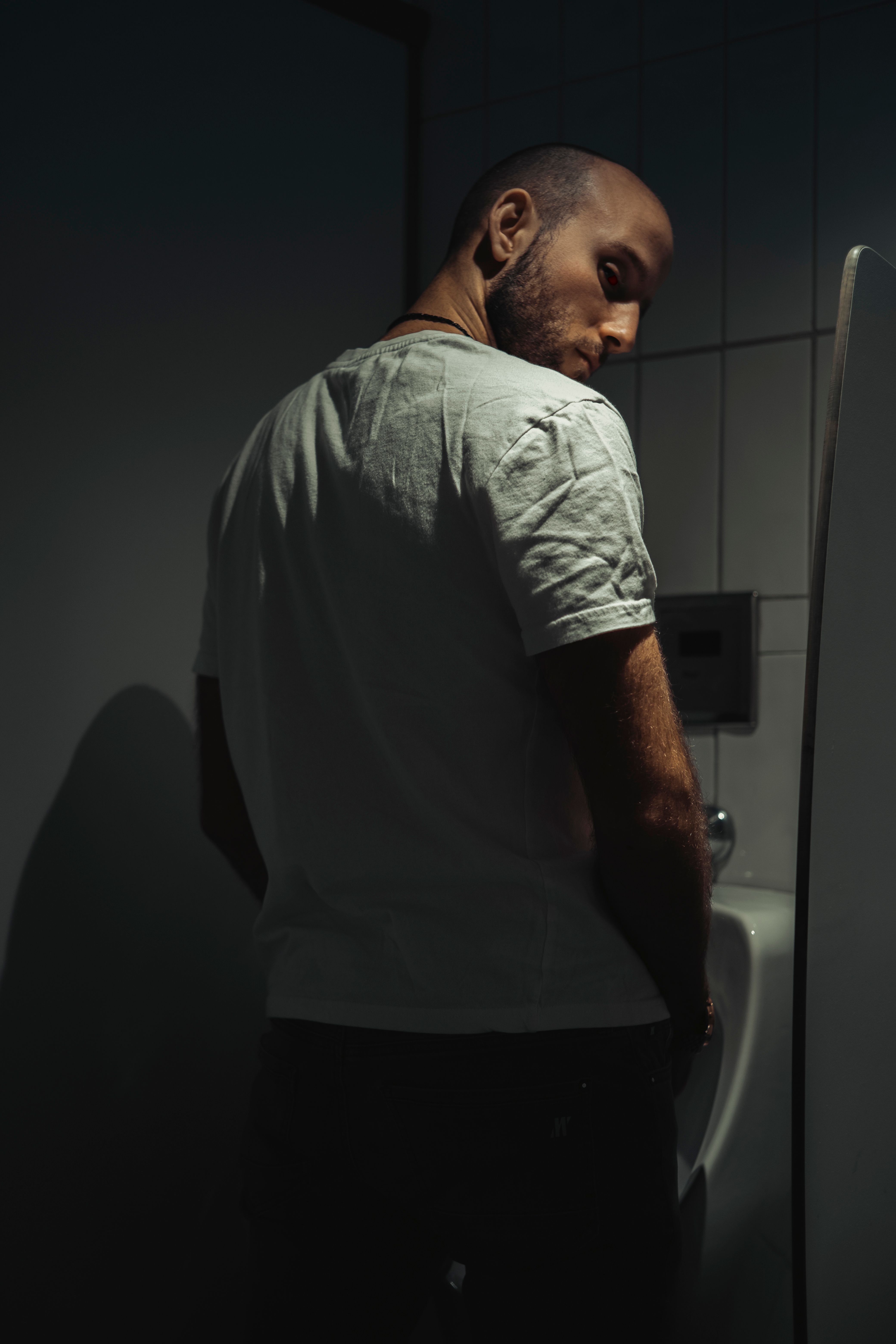 Man Standing at the Urinal in the Bathroom · Free Stock Photo