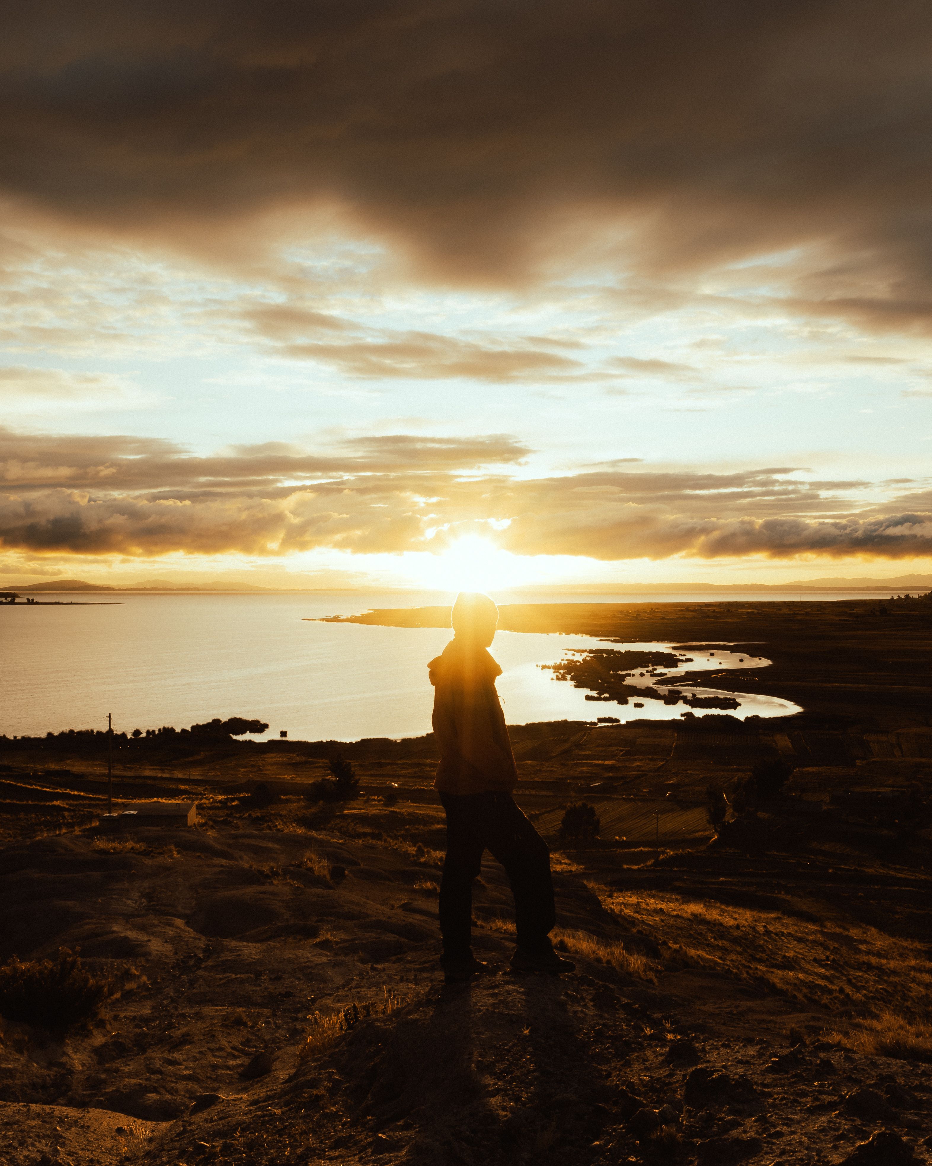 Sunset Sunlight over Man Standing on Hill over Sea Coast · Free Stock Photo