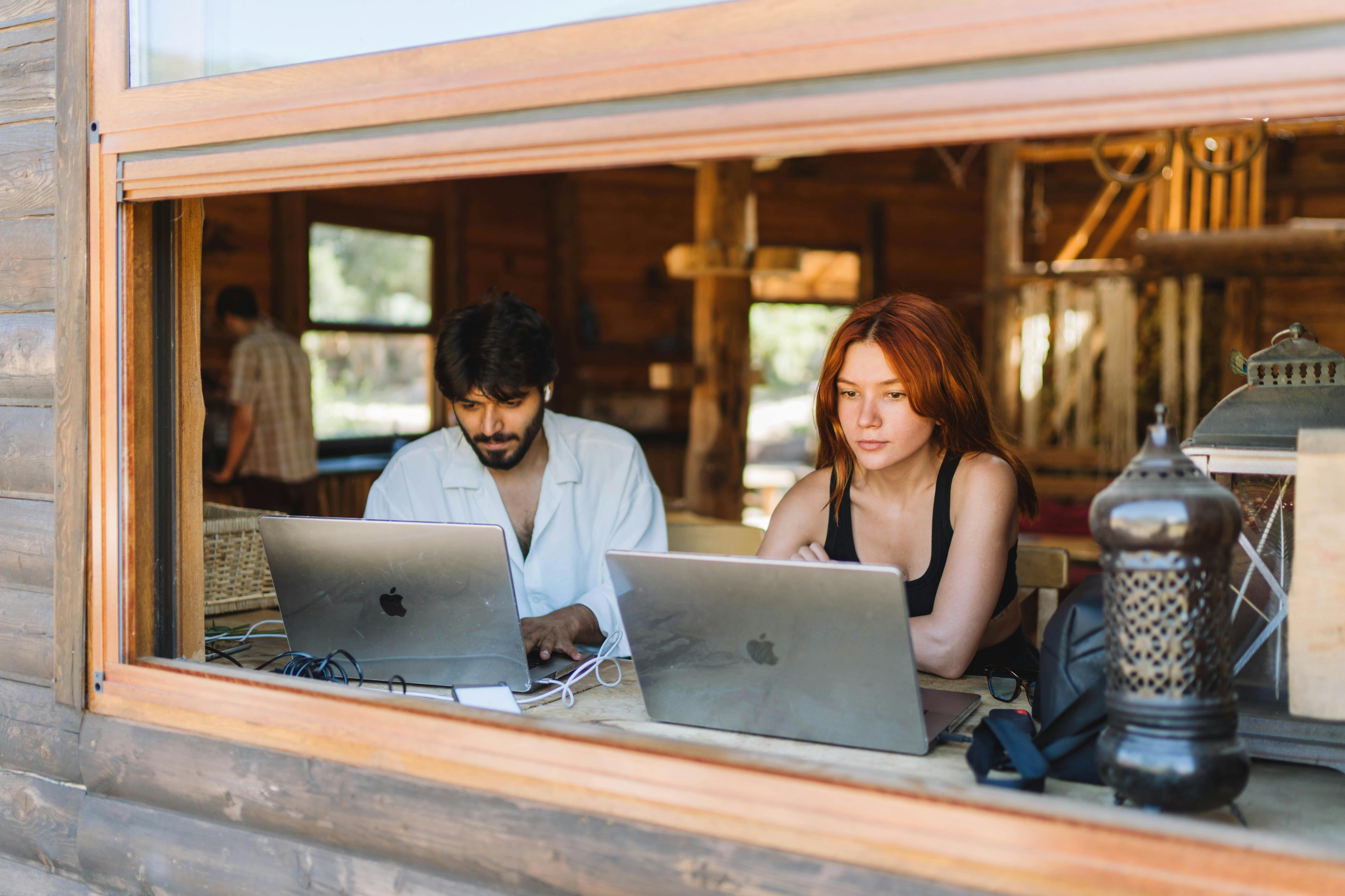 People Working on MacBooks Sitting by the Window · Free Stock Photo