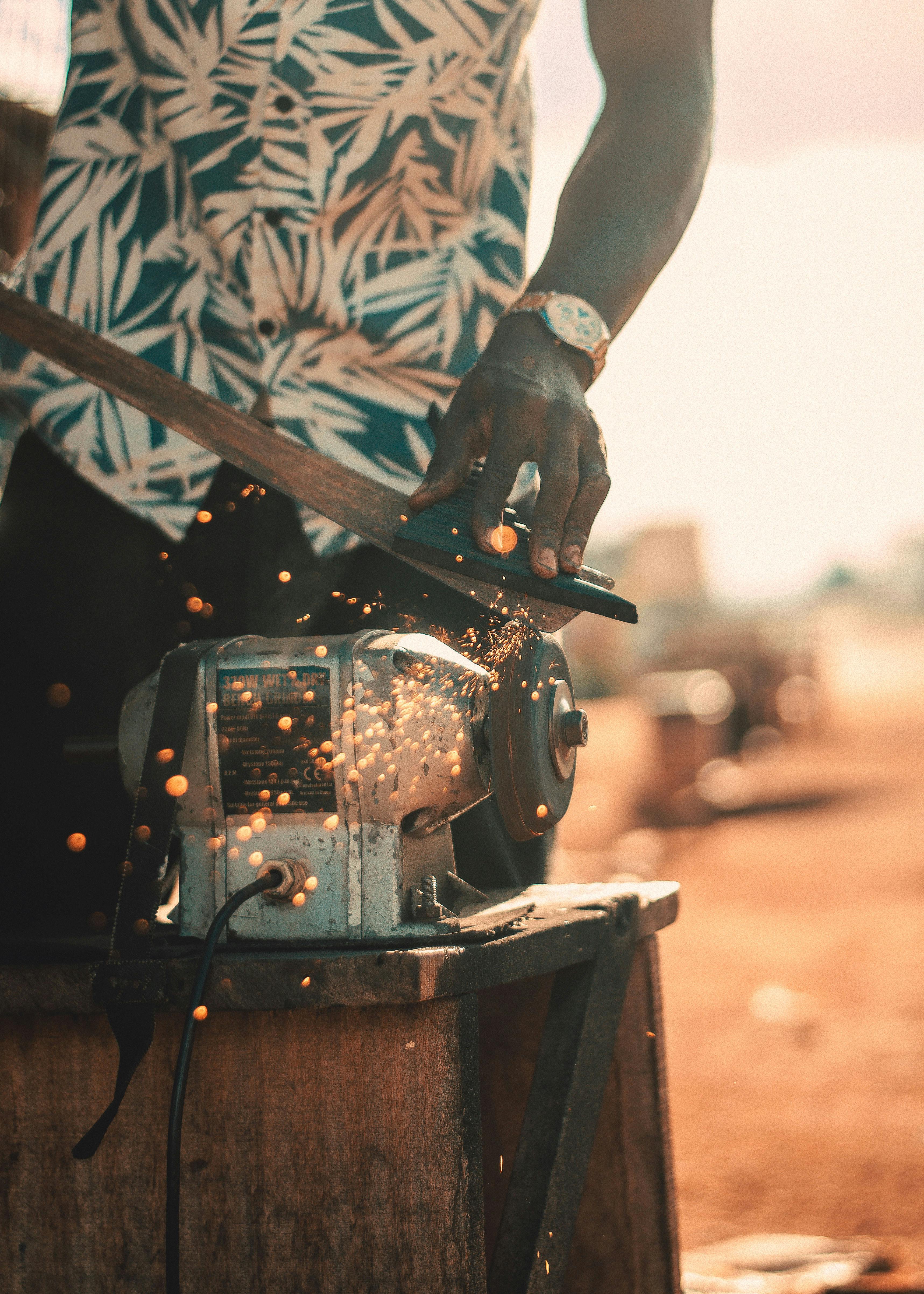 Man Using a Grinder to Make a Tool · Free Stock Photo