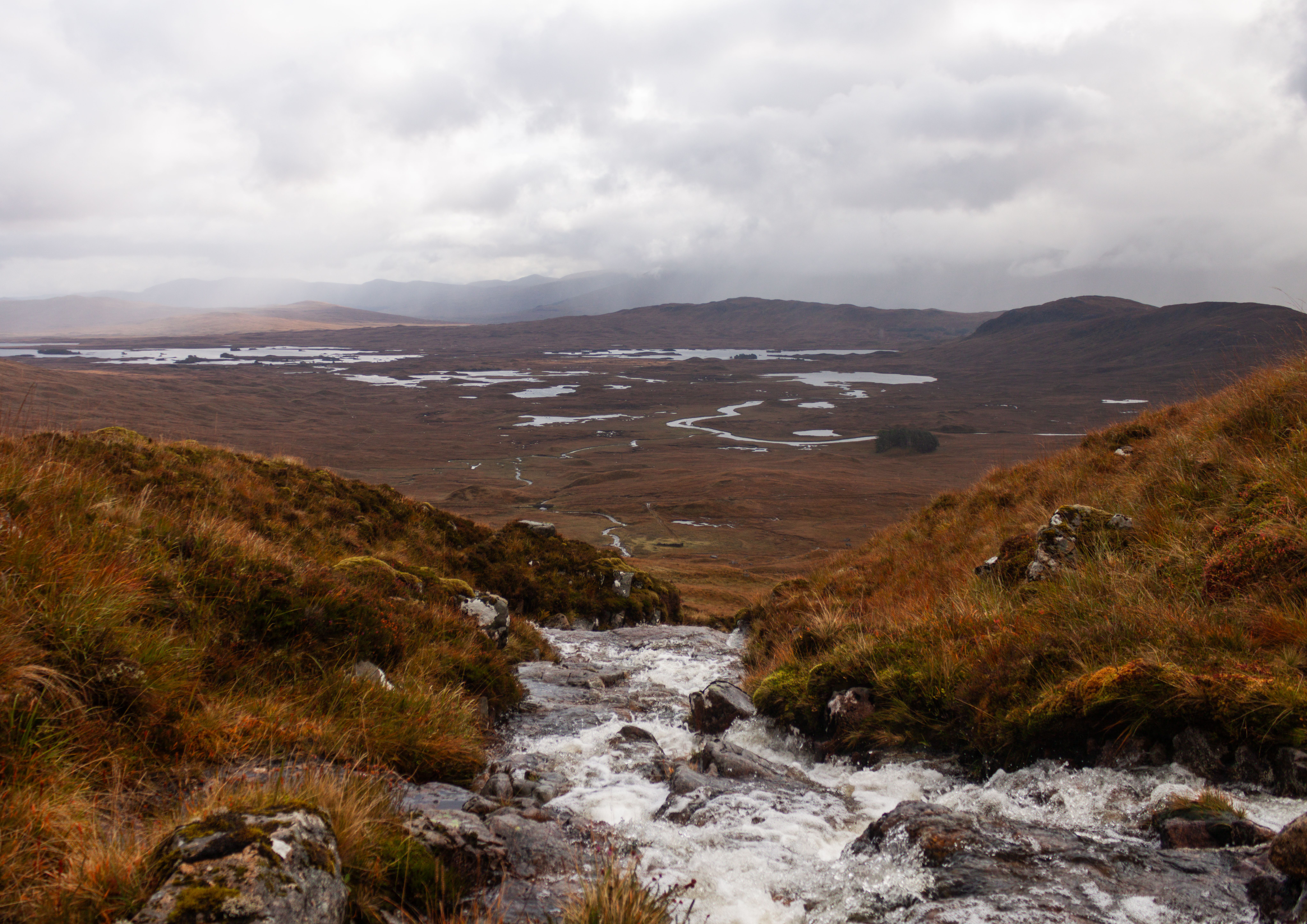 Small River Flowing through Grass Covered Hills · Free Stock Photo