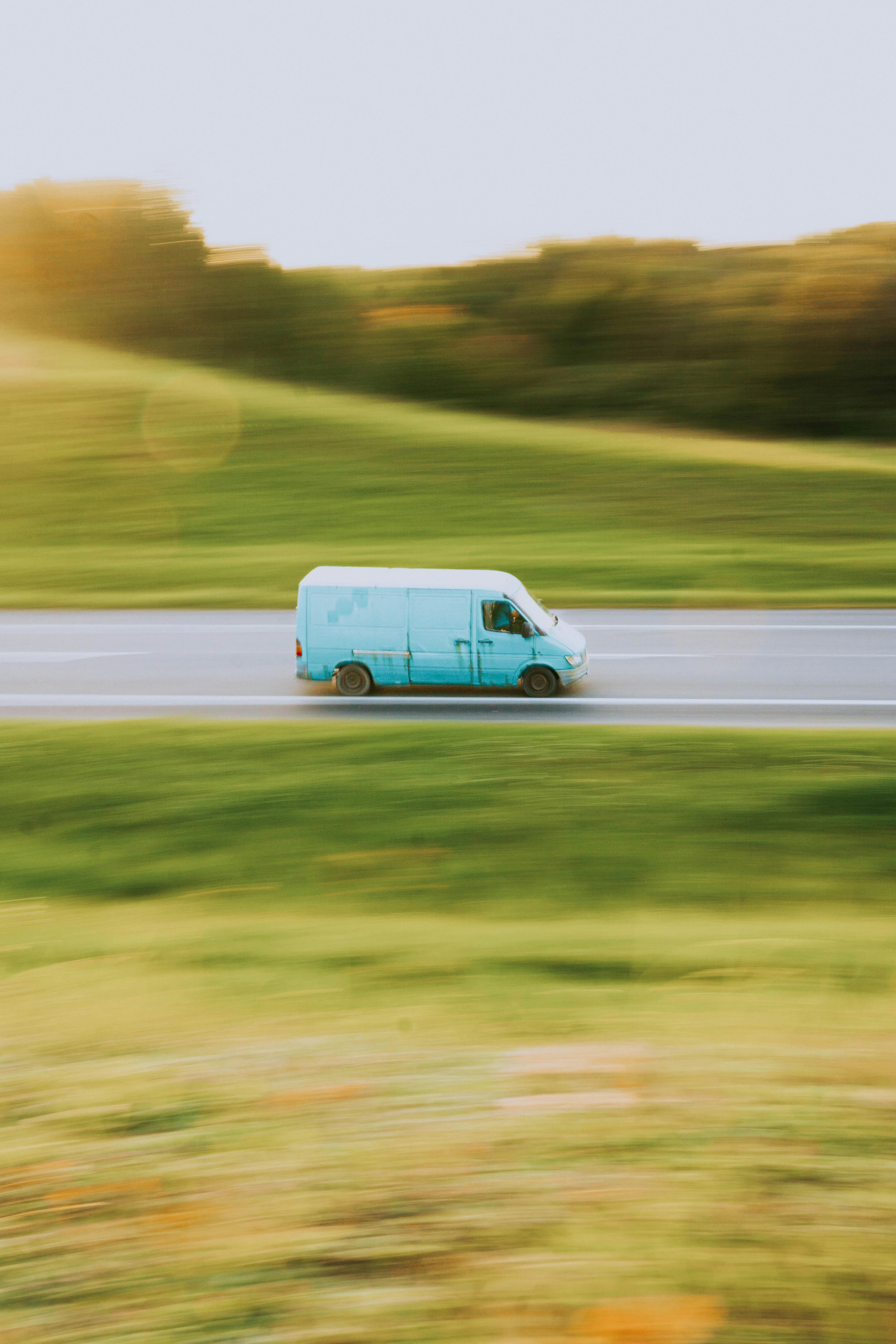a blue van driving down the highway at sunset · Free Stock Photo