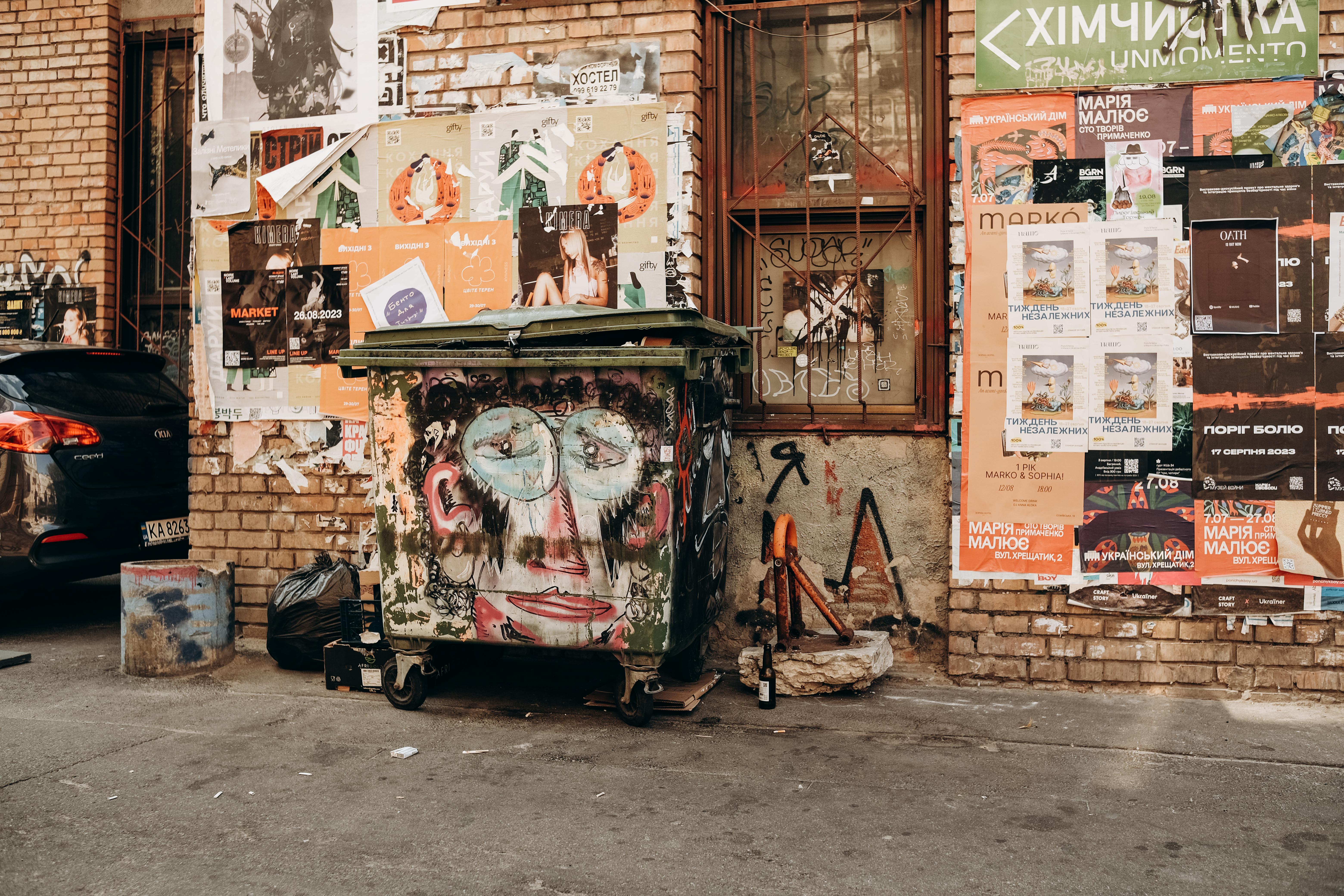 Posters on Wall over Garbage Bin in Alley in Town · Free Stock Photo
