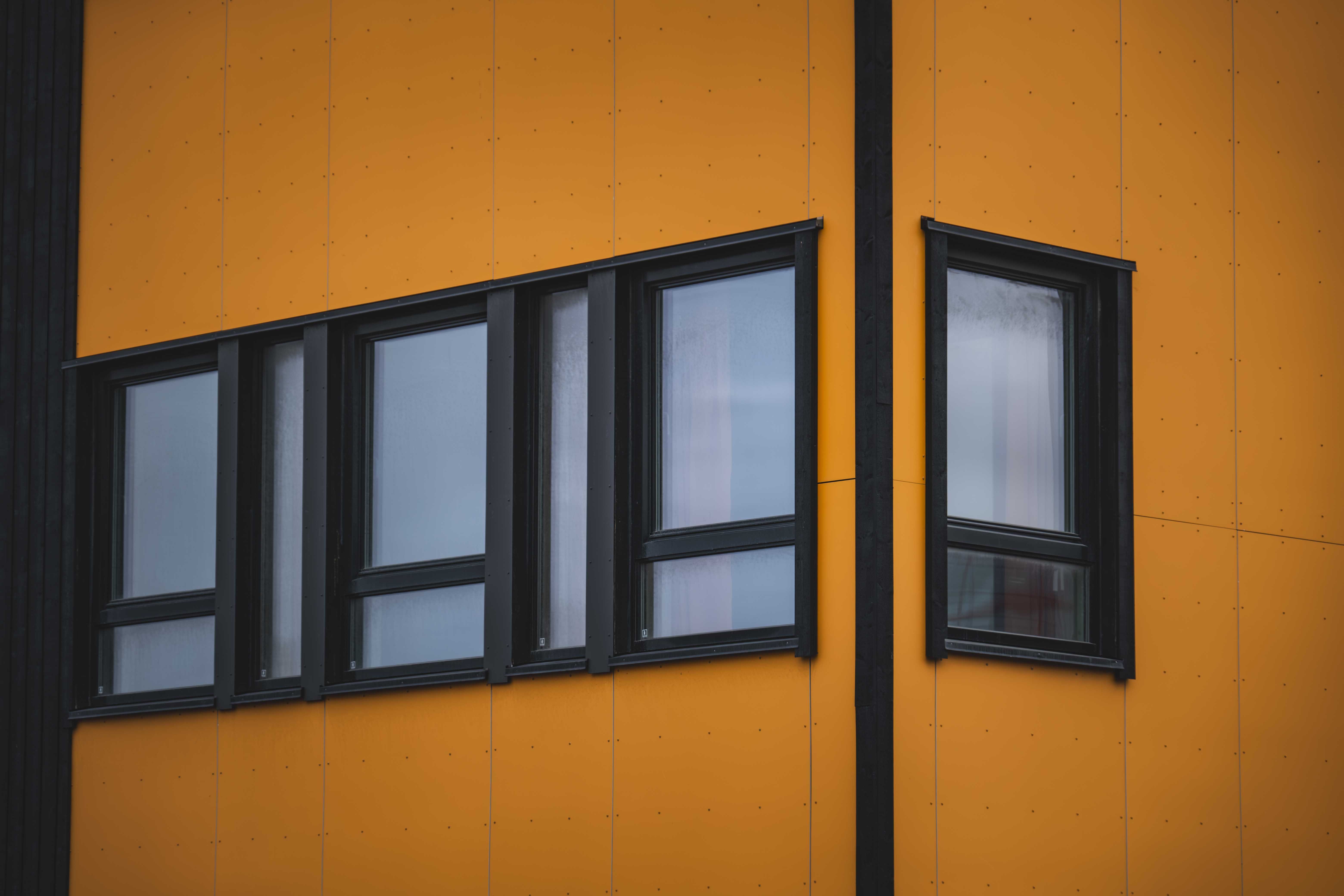 Facade of a Yellow Building with Black Window Frames · Free Stock Photo