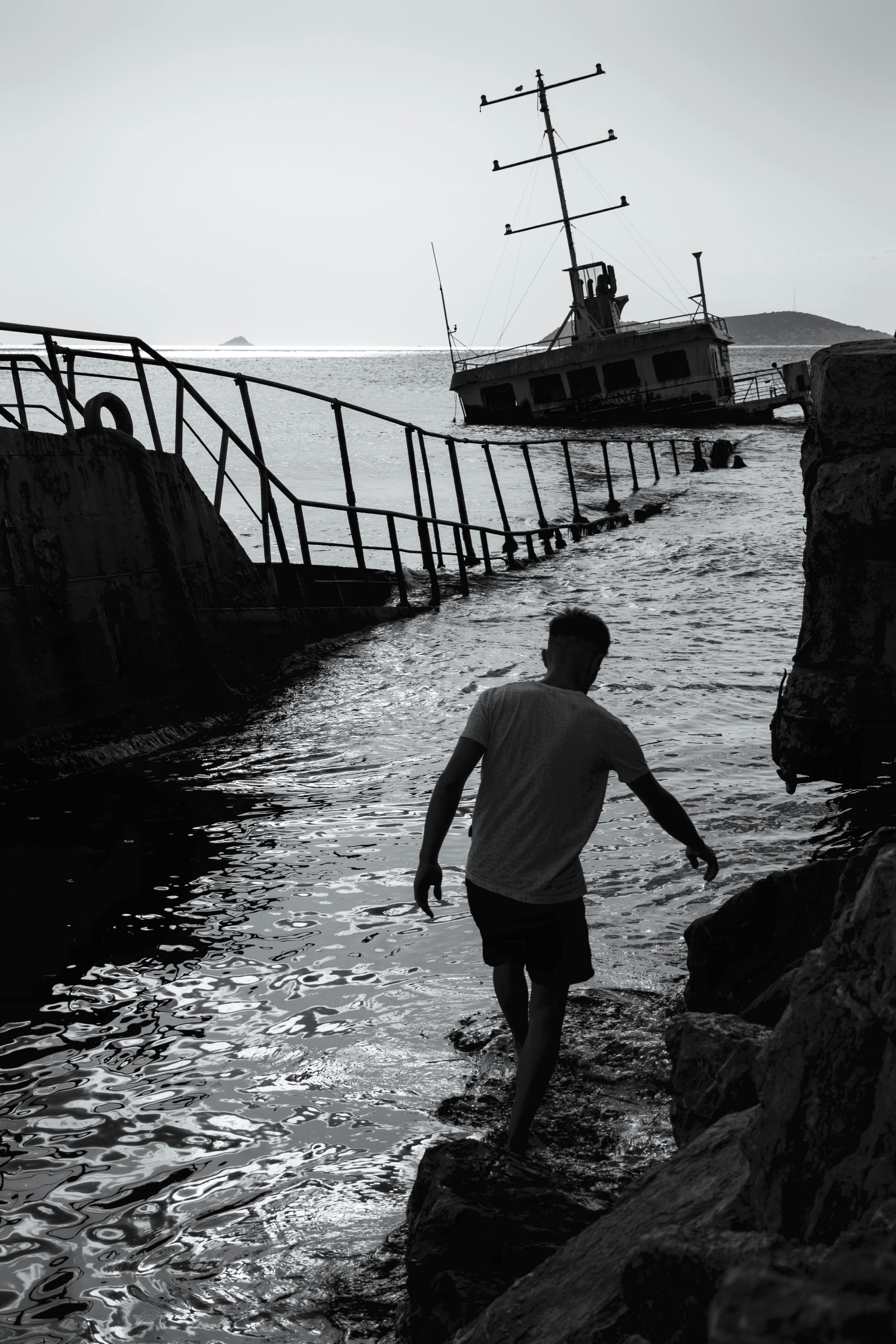 Man Wading into Sea Towards a Boat · Free Stock Photo