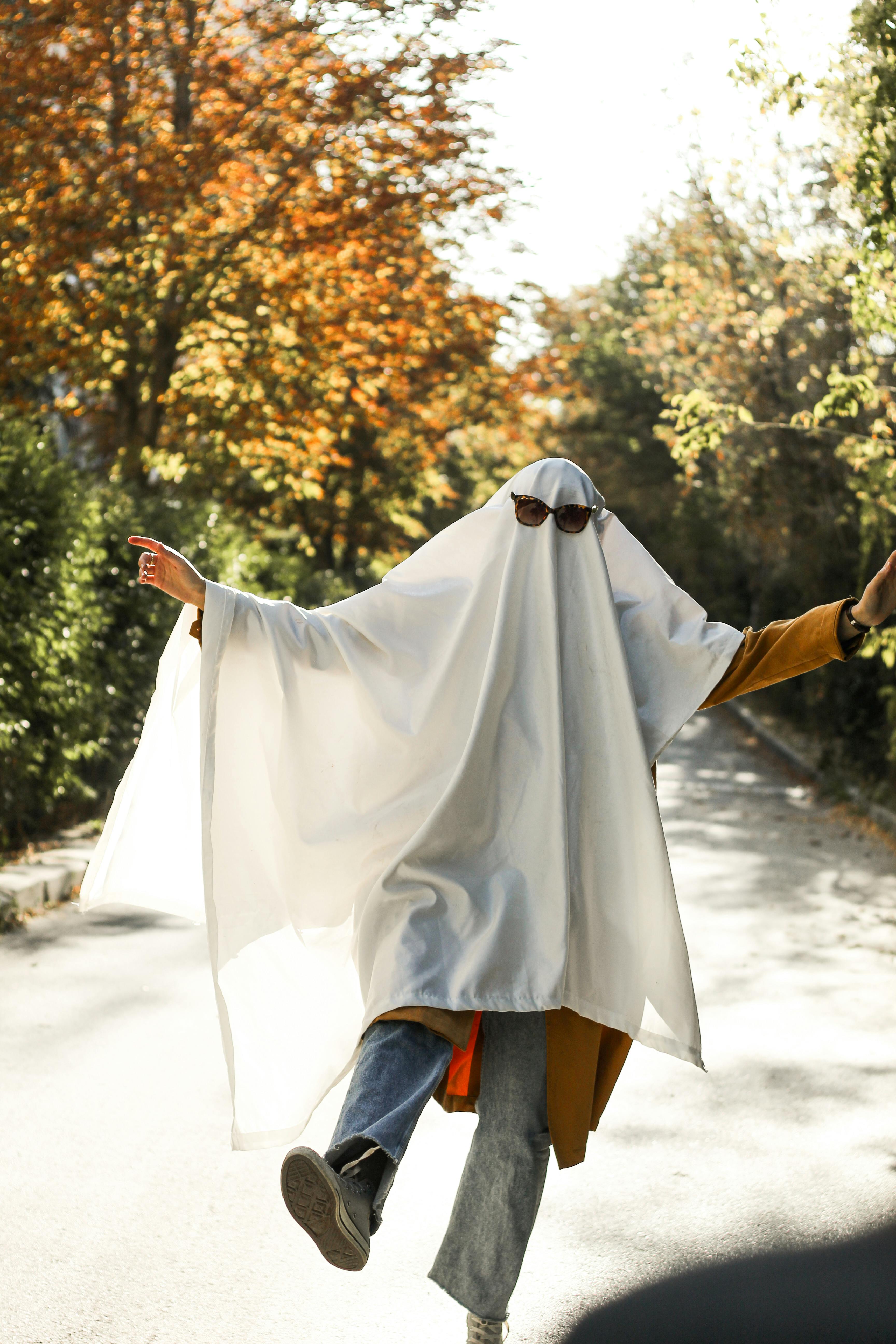 People Dressed as Ghost by a Pumpkin Decoration · Free Stock Photo