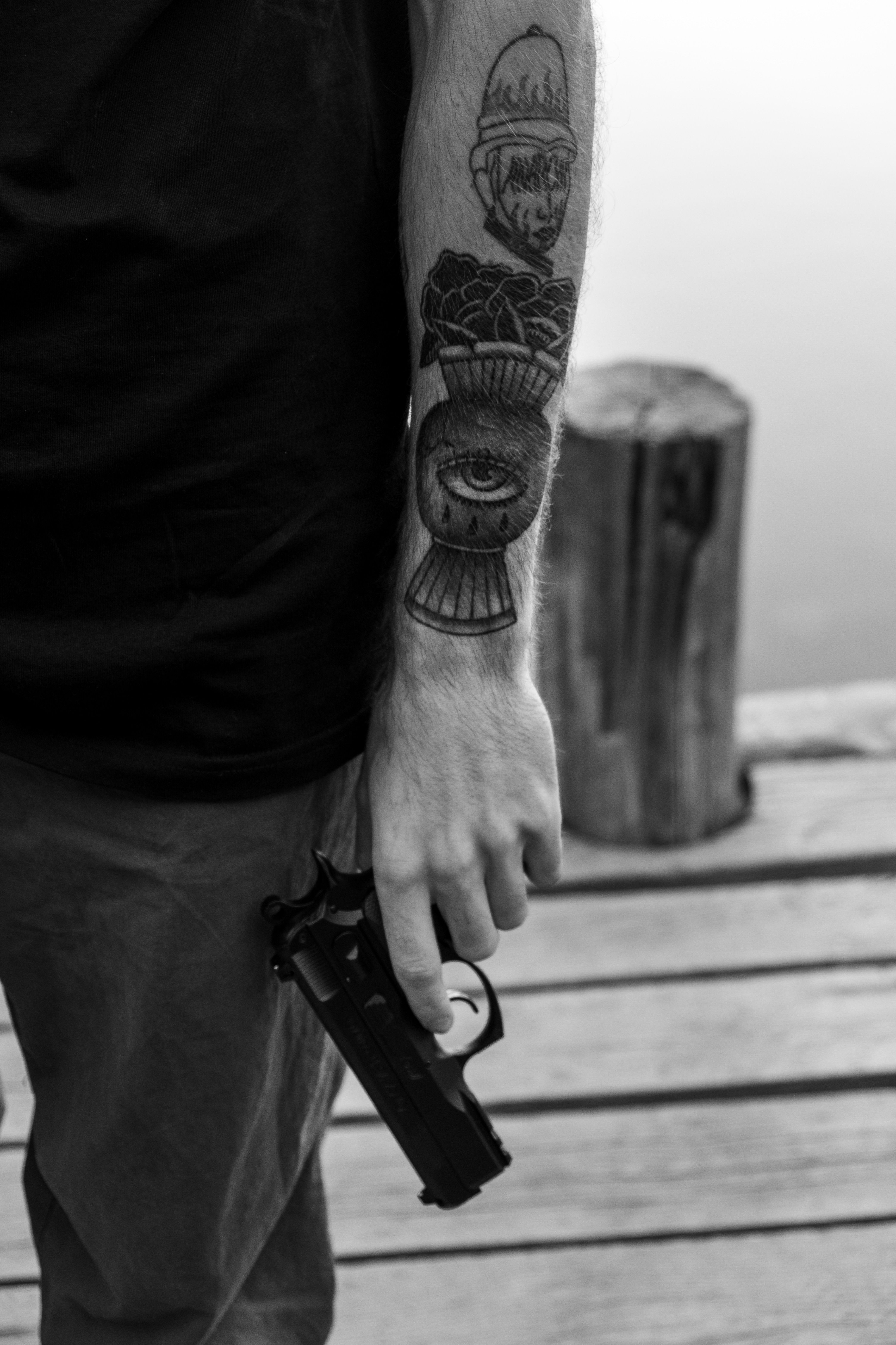 Man with Tattoos Holding a Gun Standing on a Pier · Free Stock Photo