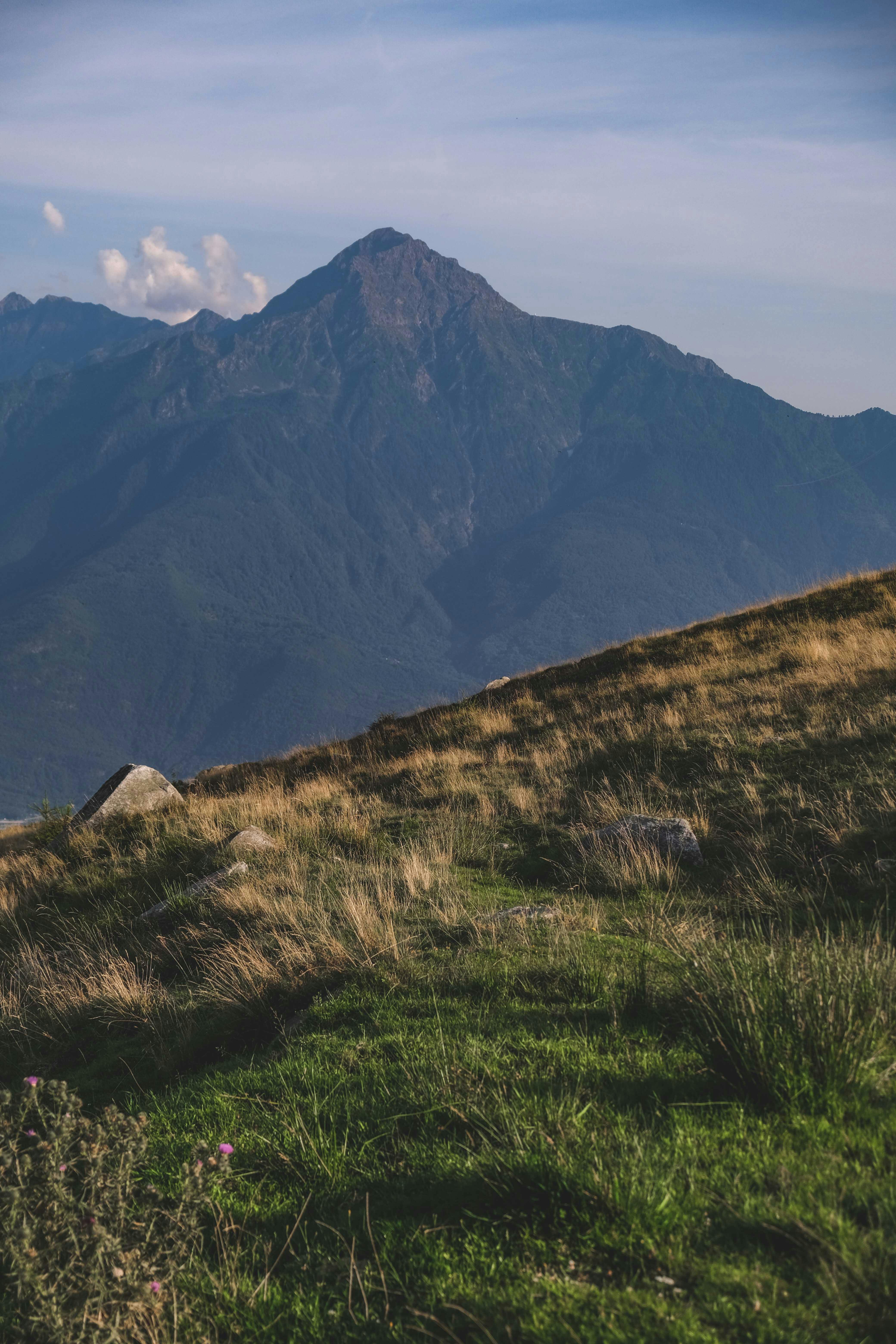 Green Hill and a Distant Mountain Range · Free Stock Photo