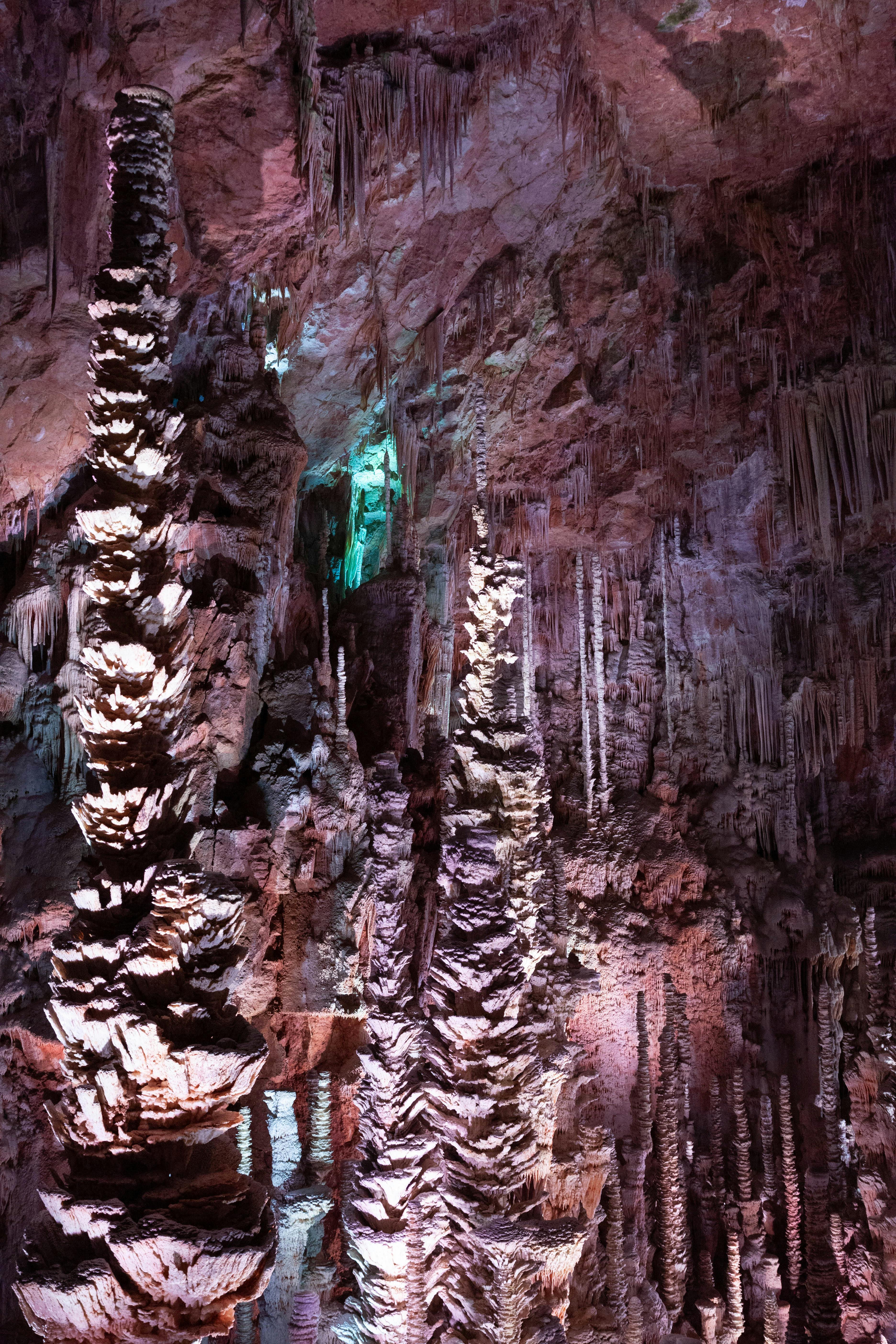 A cave with many tall pillars and a green light · Free Stock Photo