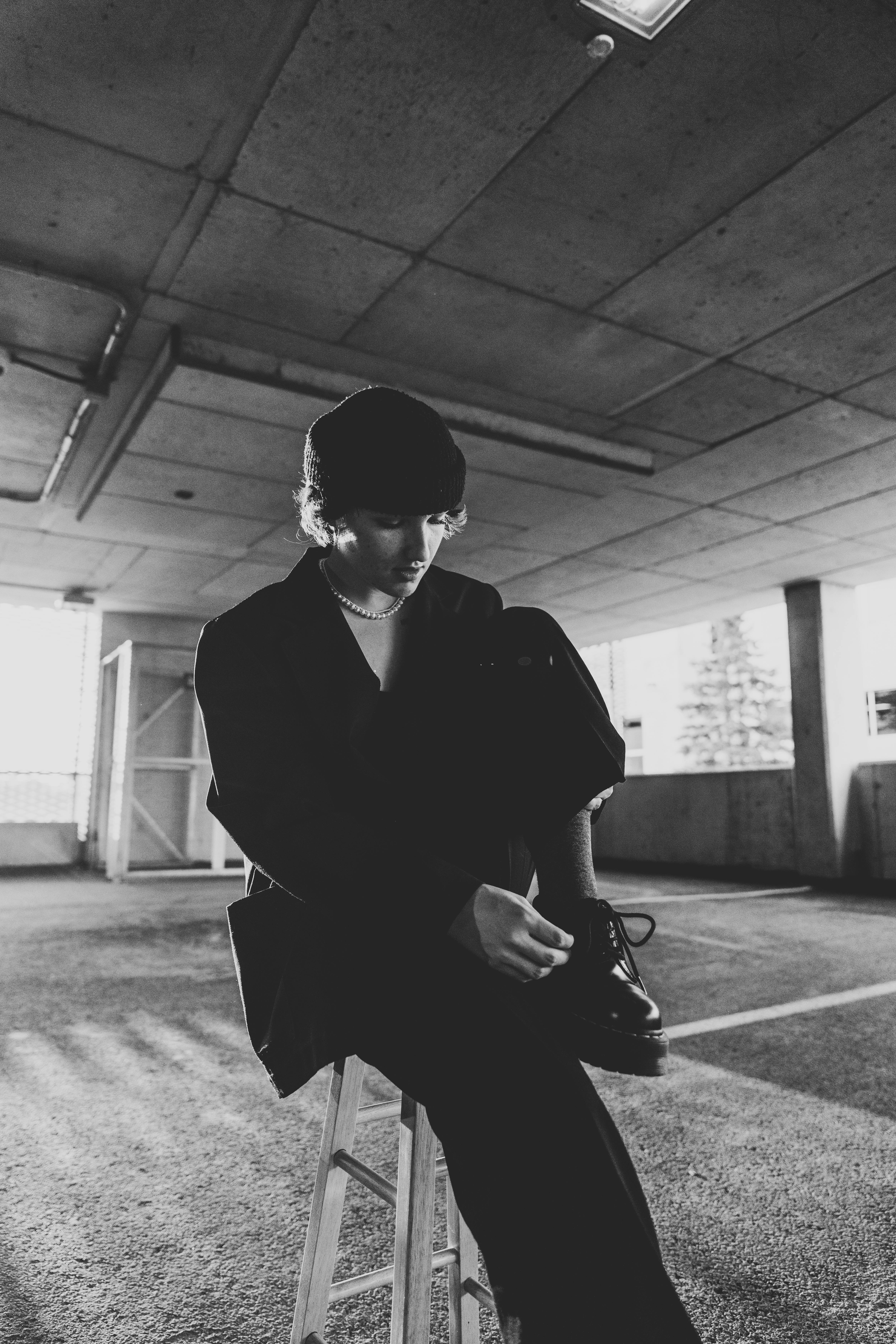 A man sitting on a stool in an empty parking garage · Free Stock Photo