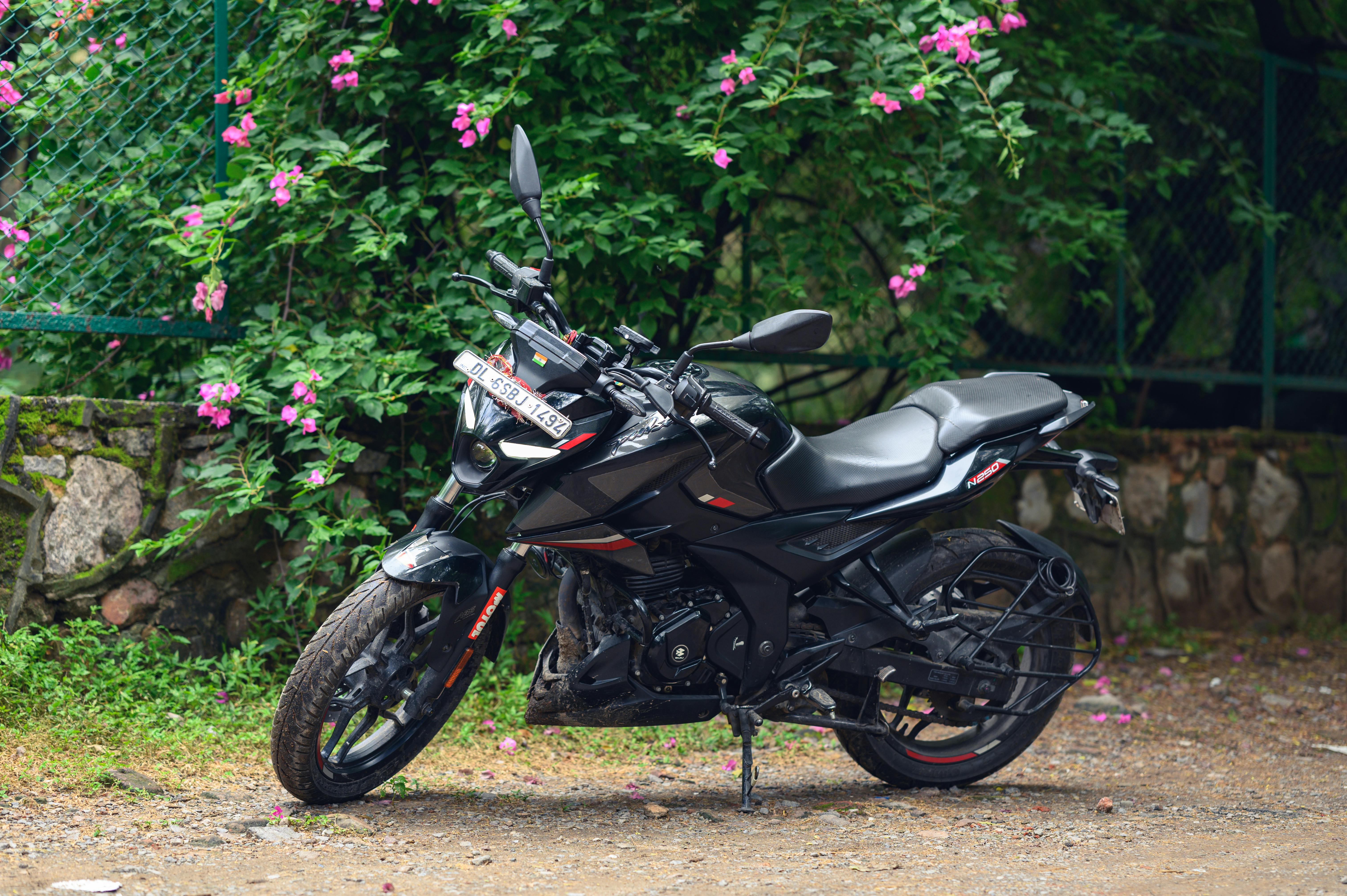 A Bajaj Pulsar Motorcycle Parked near a Shrub with Flowers · Free Stock ...