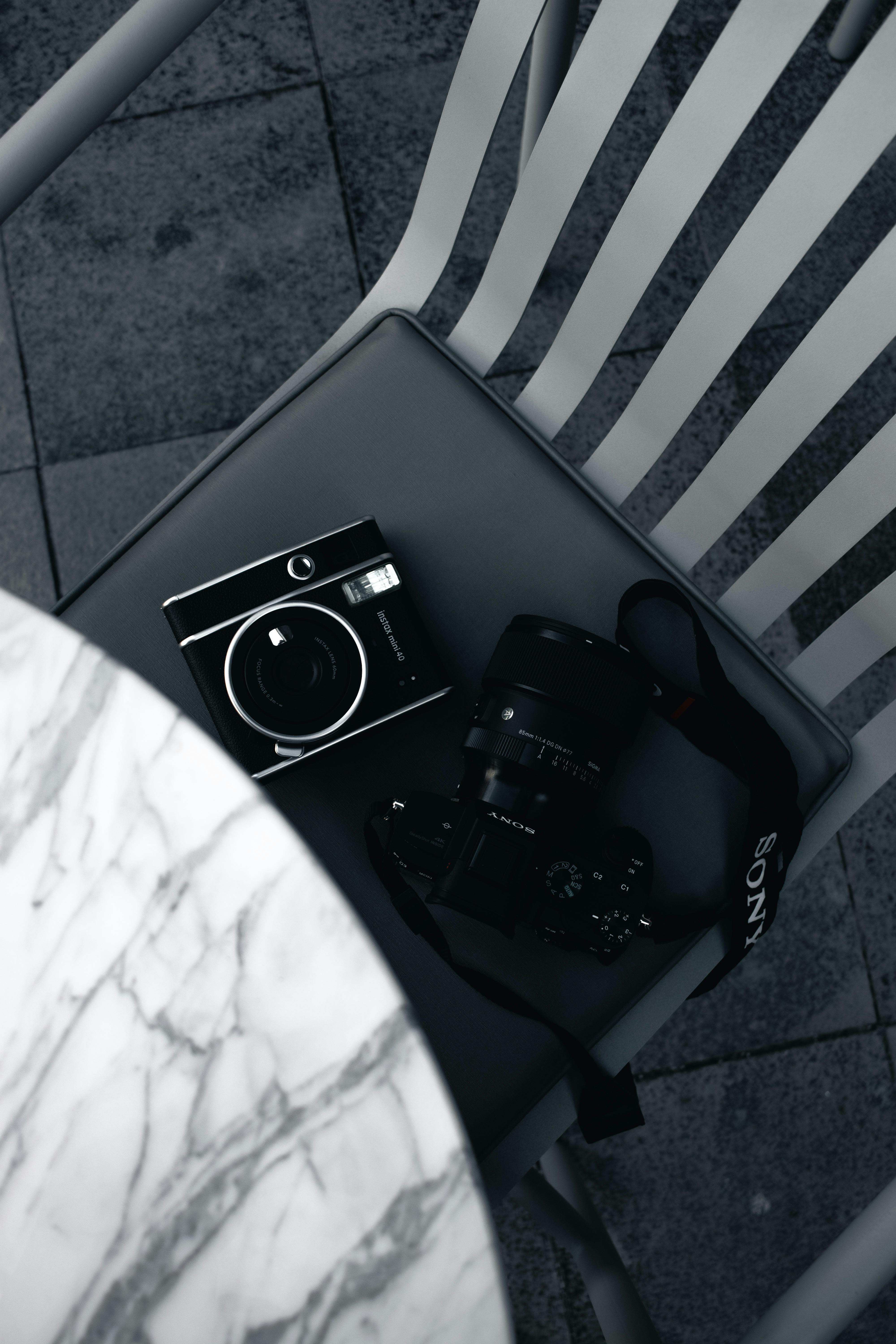 A Polaroid Camera and an SLR Camera Lying on a Chair · Free Stock Photo