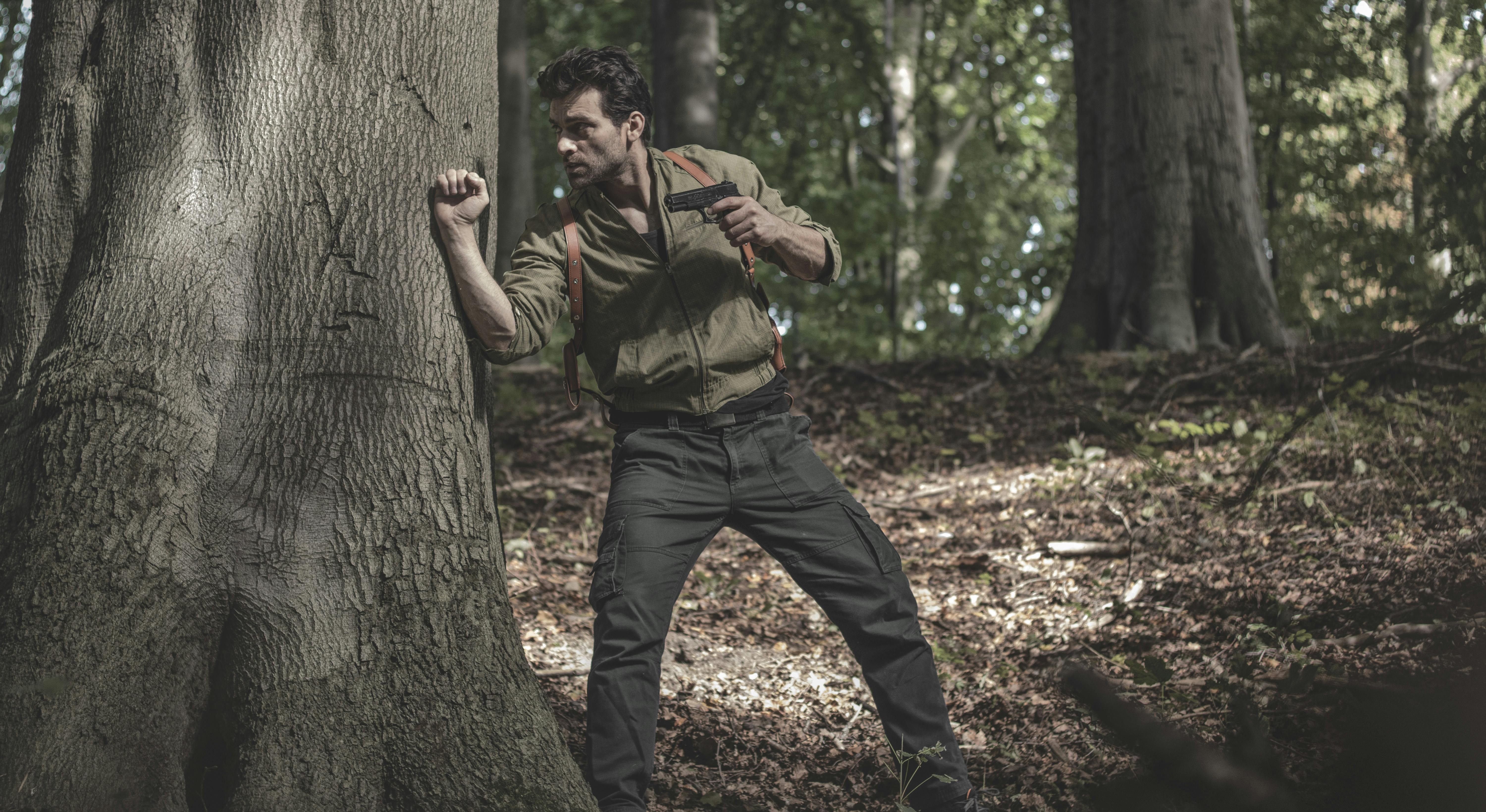 Man Holding a Gun in a Forest · Free Stock Photo