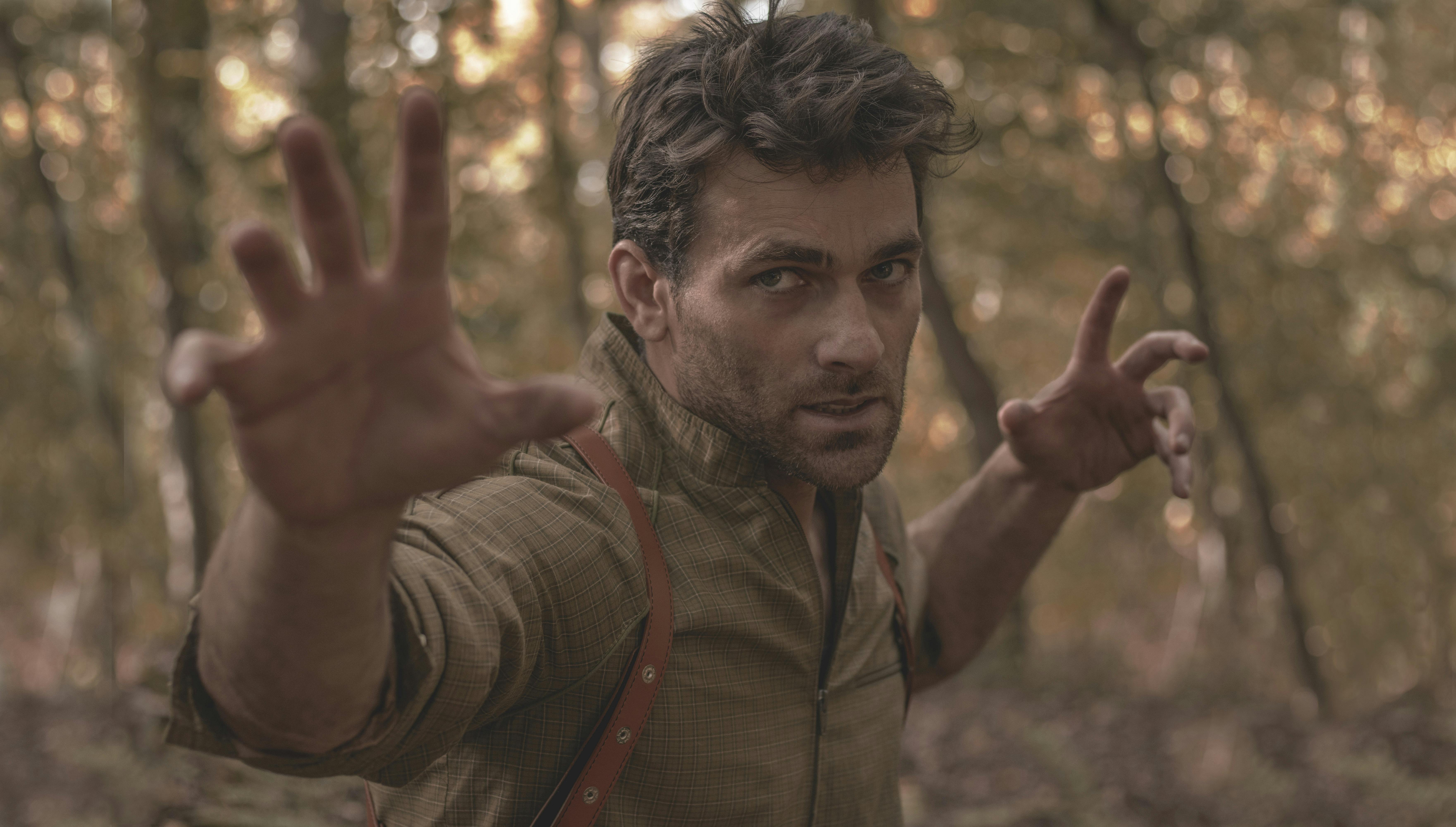 Beige Toned Image of a Man Gesturing in a Forest · Free Stock Photo