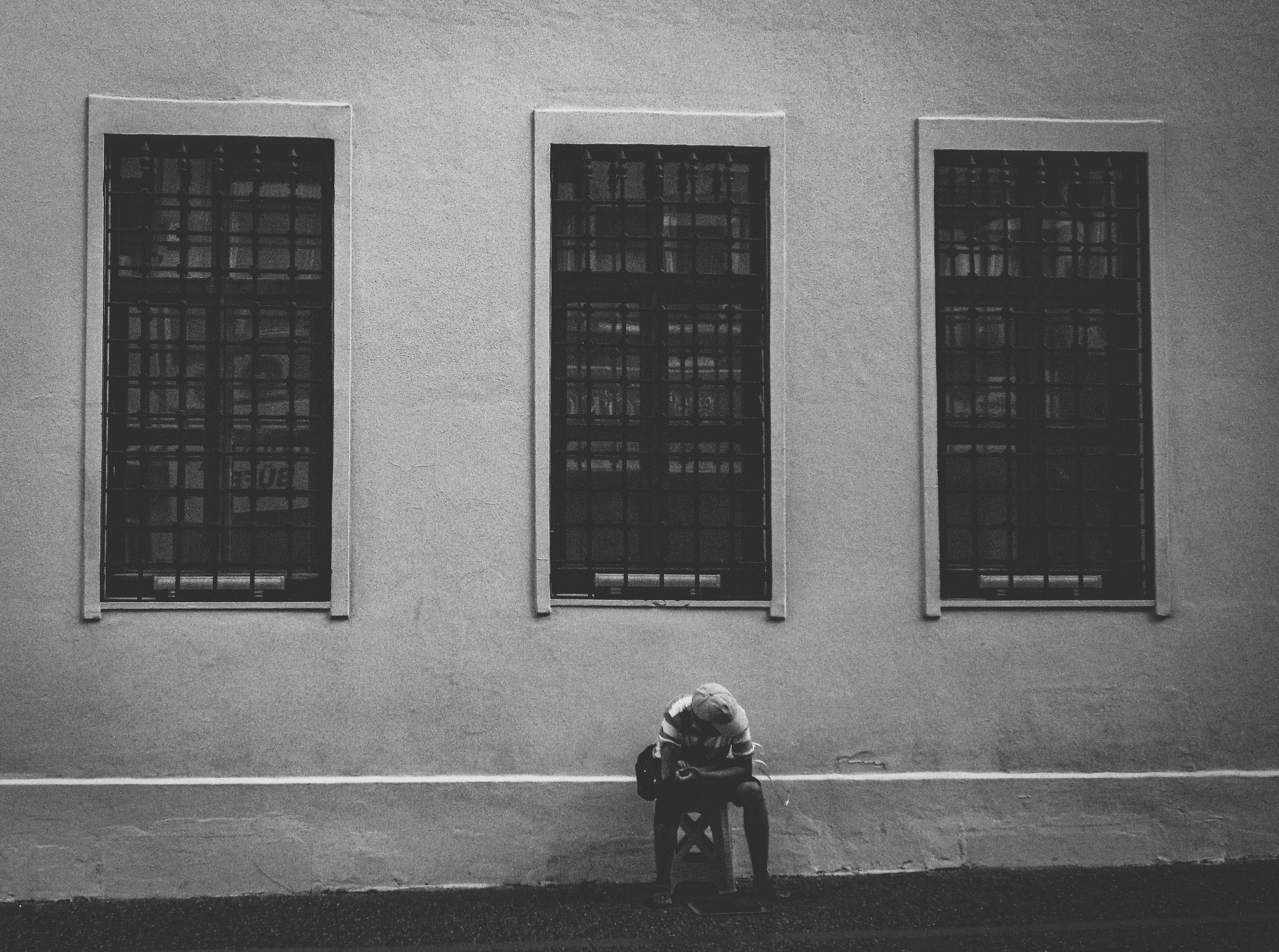 Man Sitting by Building Wall · Free Stock Photo