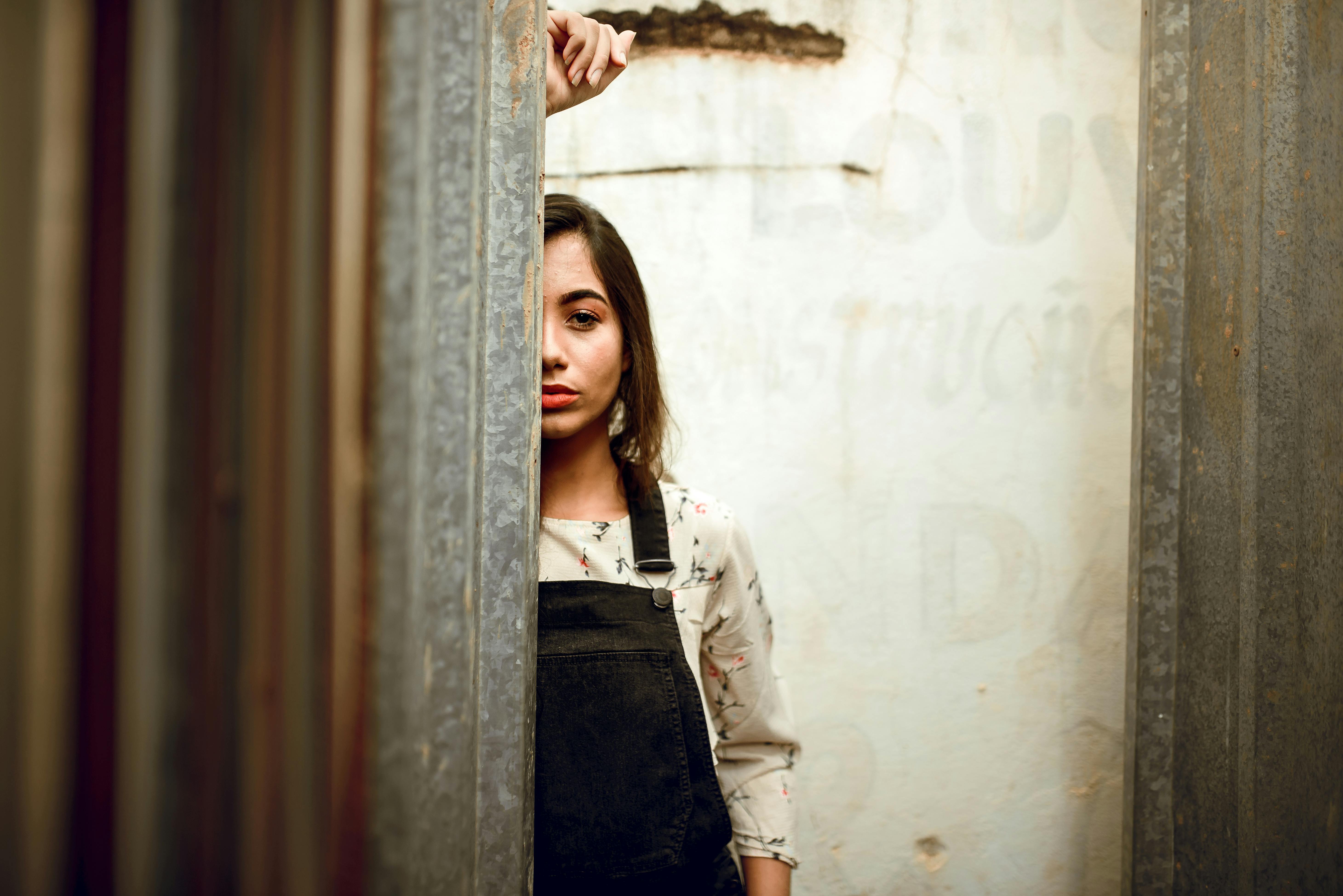 Woman In White Top Standing Behind Wall · Free Stock Photo