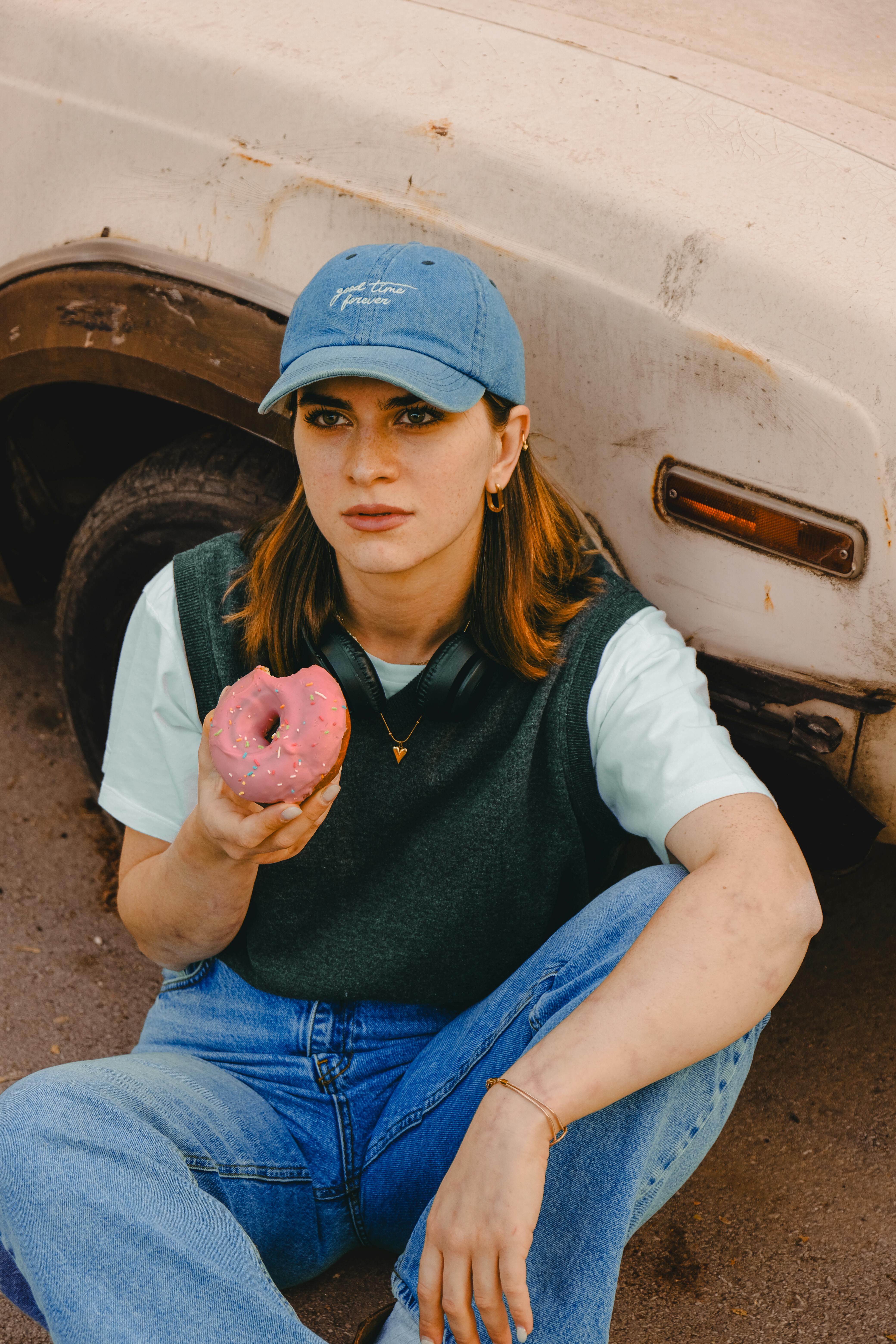 Woman in Jean Jacket Lying Down and Eating Donut · Free Stock Photo