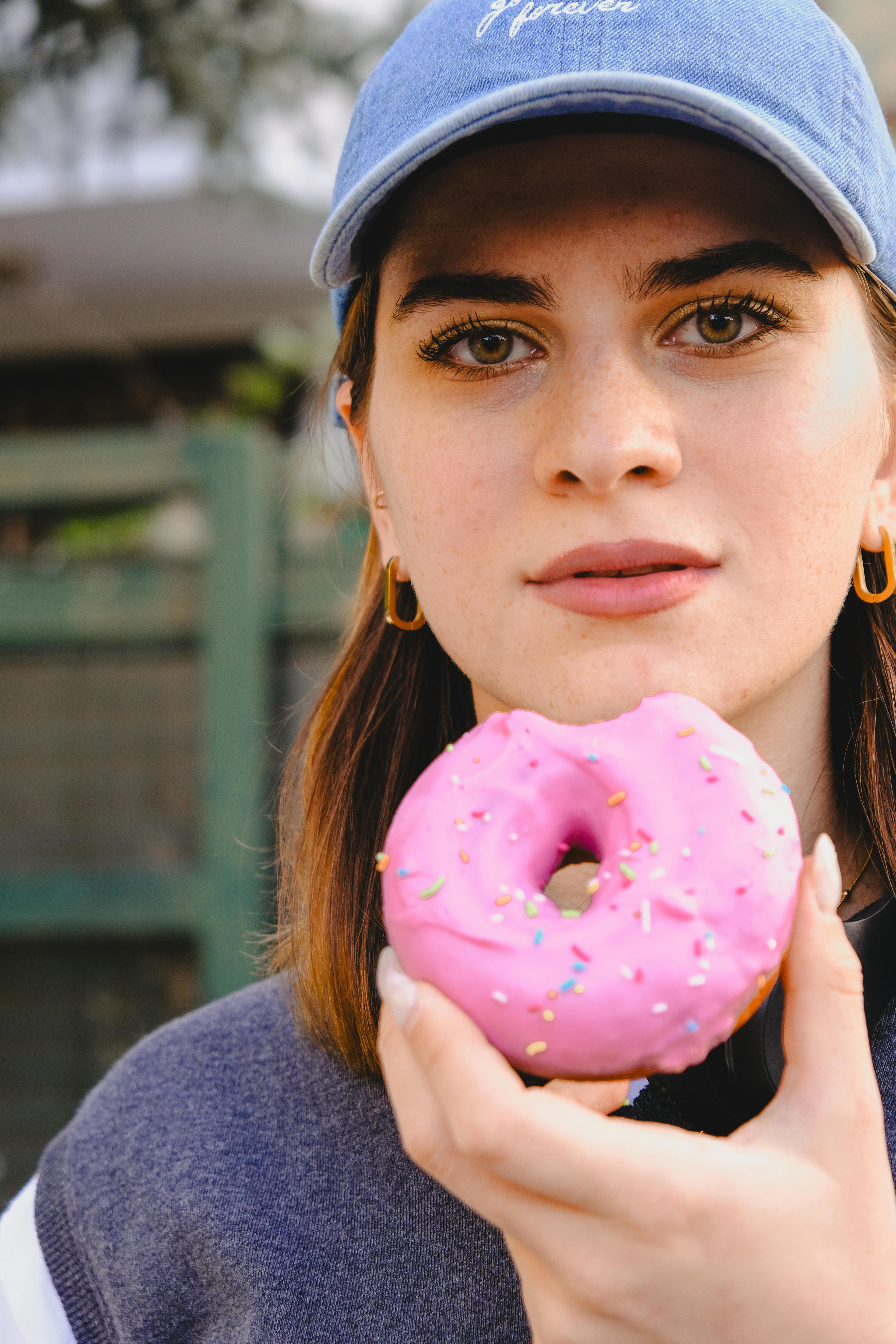 Woman in Jean Jacket Lying Down and Eating Donut · Free Stock Photo