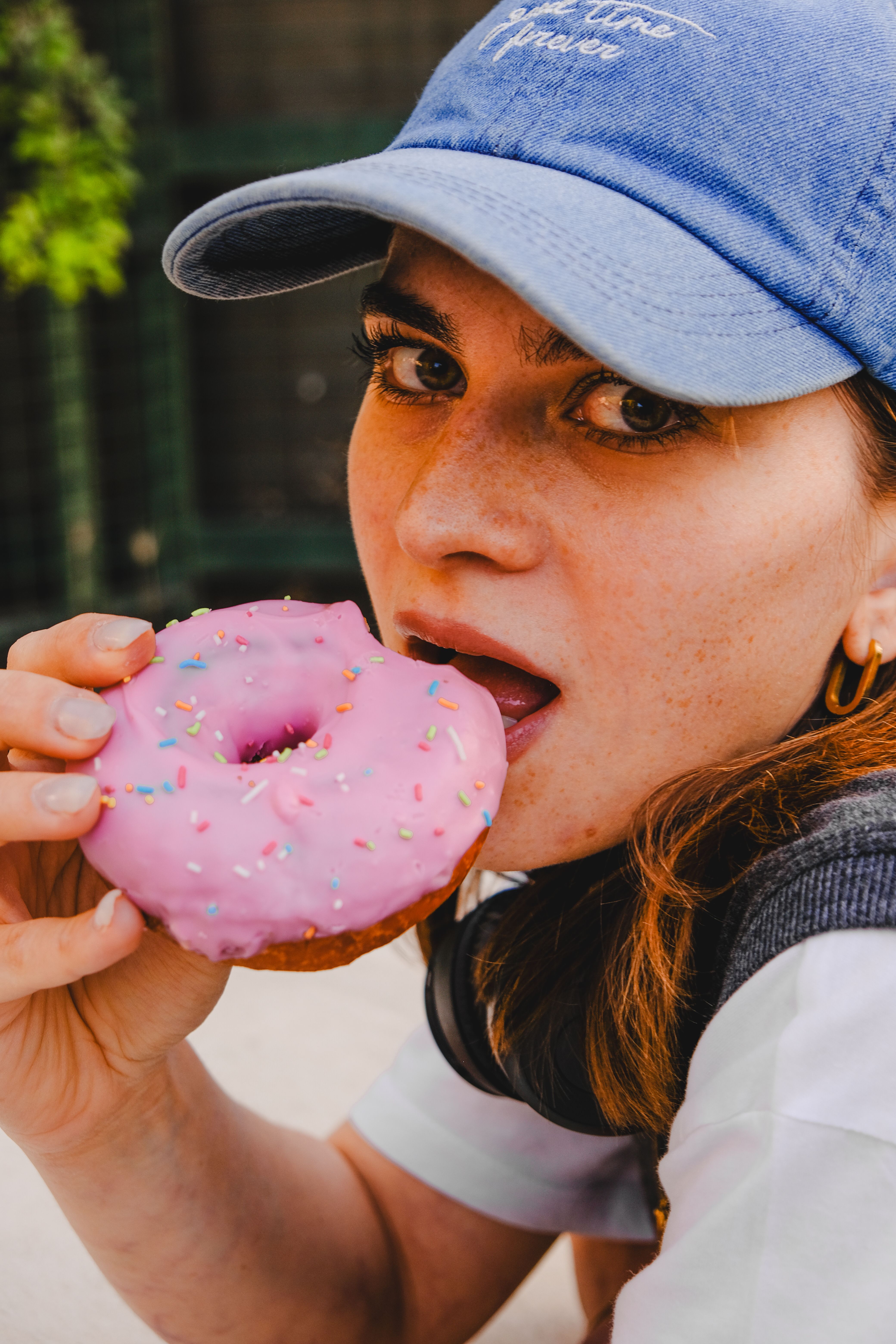 Woman in Jean Jacket Lying Down and Eating Donut · Free Stock Photo