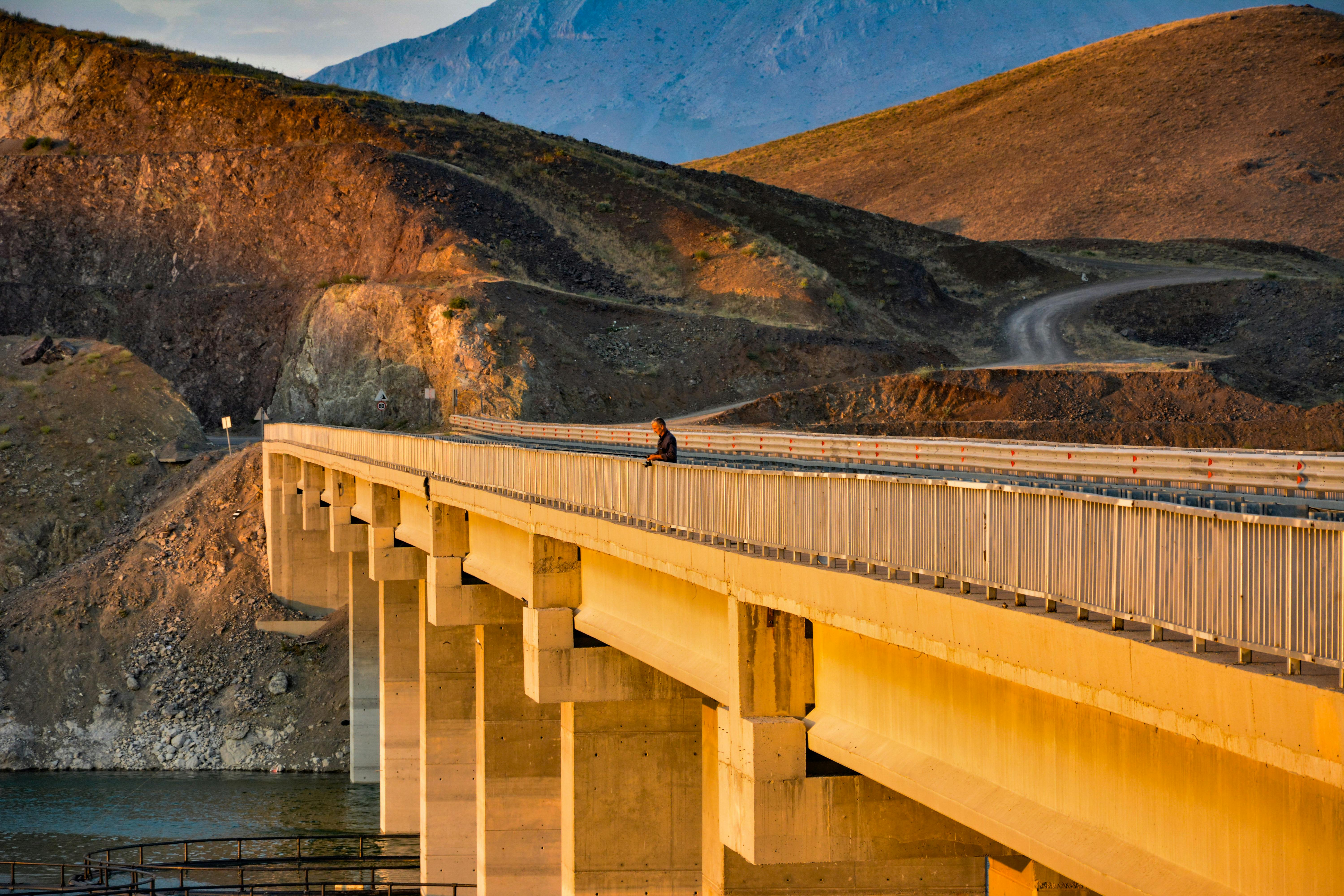 Man Standing on Bridge at Sunset · Free Stock Photo