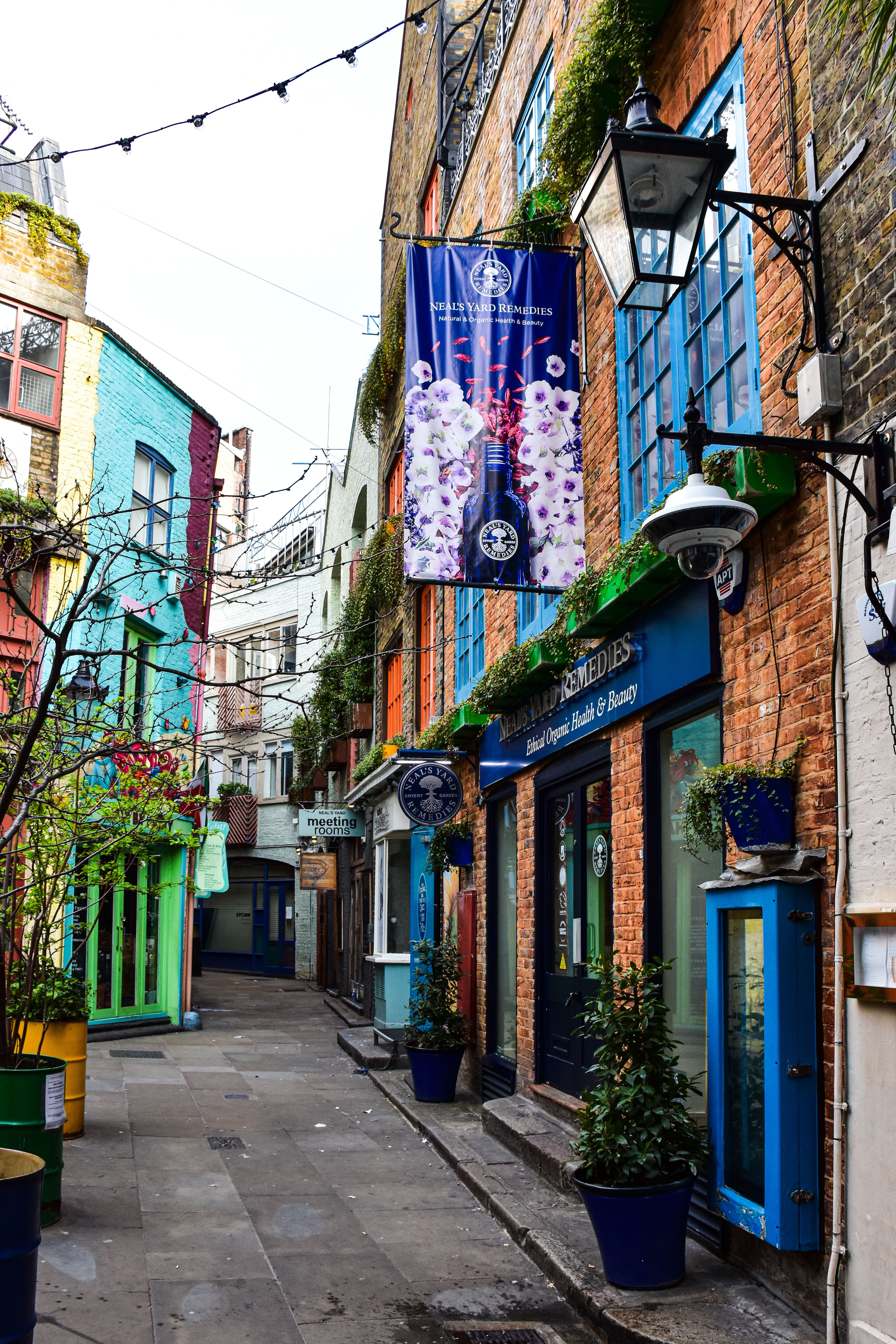 A narrow alley with colorful buildings and blue lights · Free Stock Photo