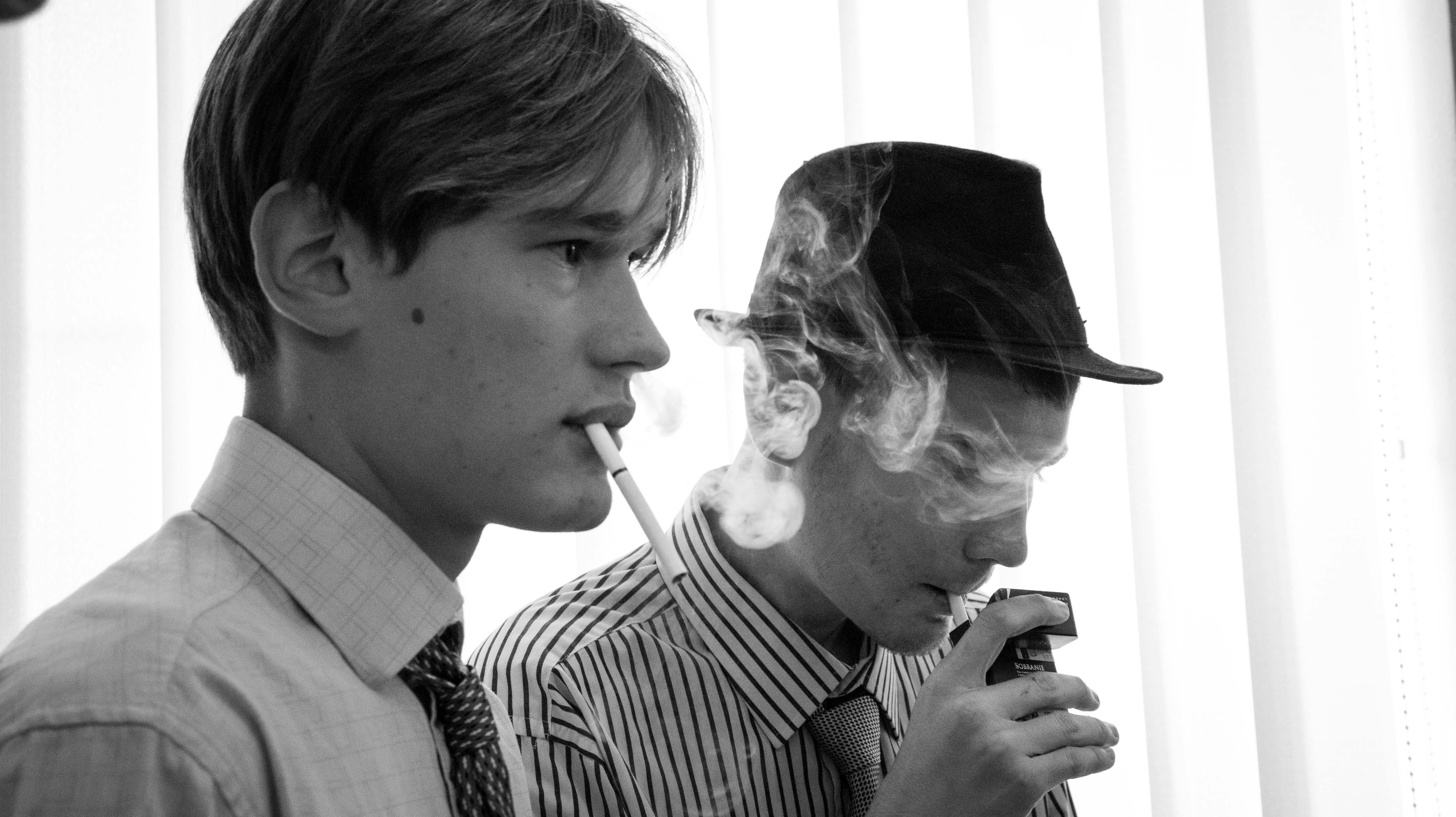 Two men smoking cigarettes while one is wearing a hat · Free Stock Photo