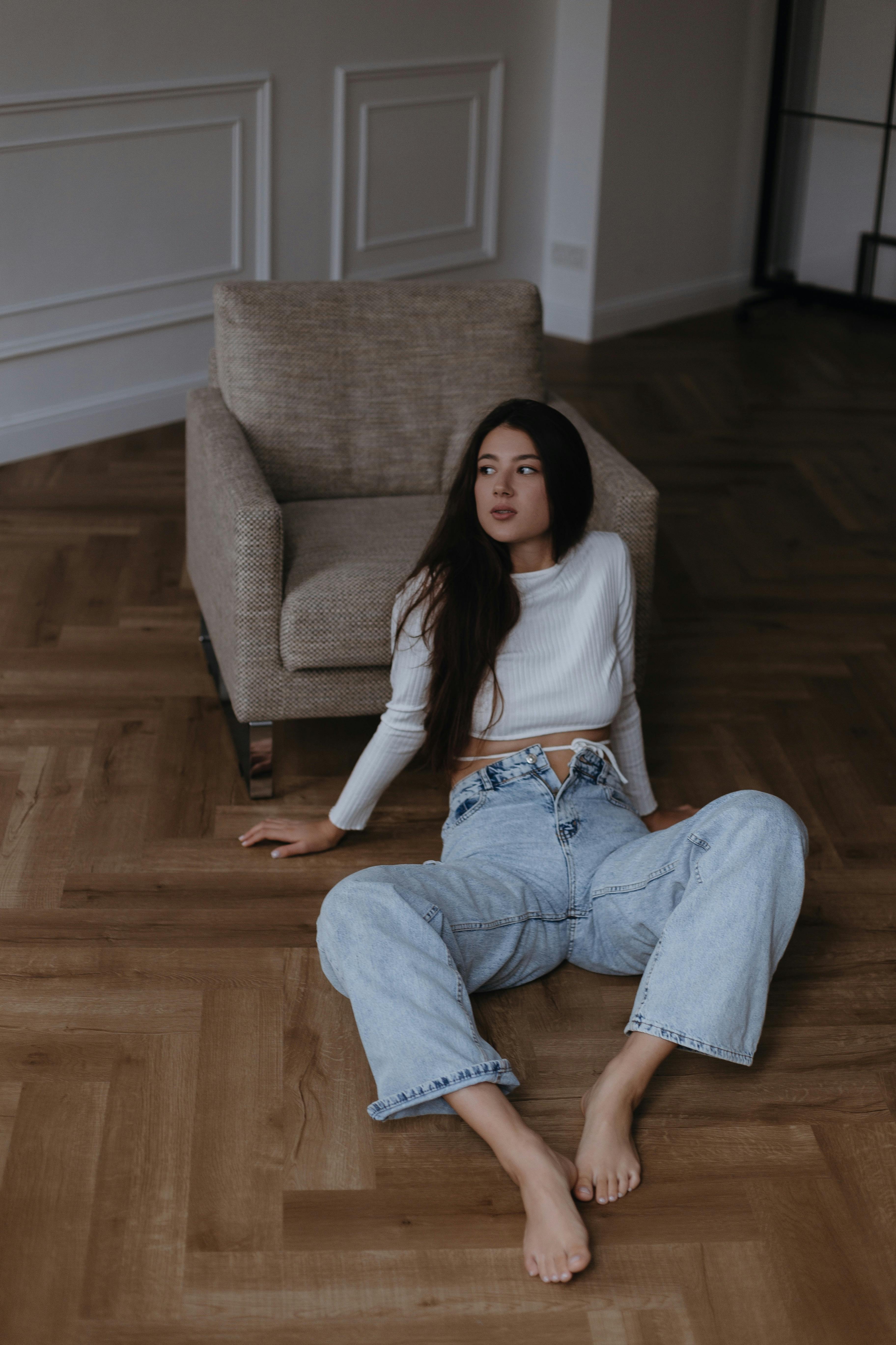 Young Woman in White Long Sleeved Top and Blue Flared Jeans Sitting on ...