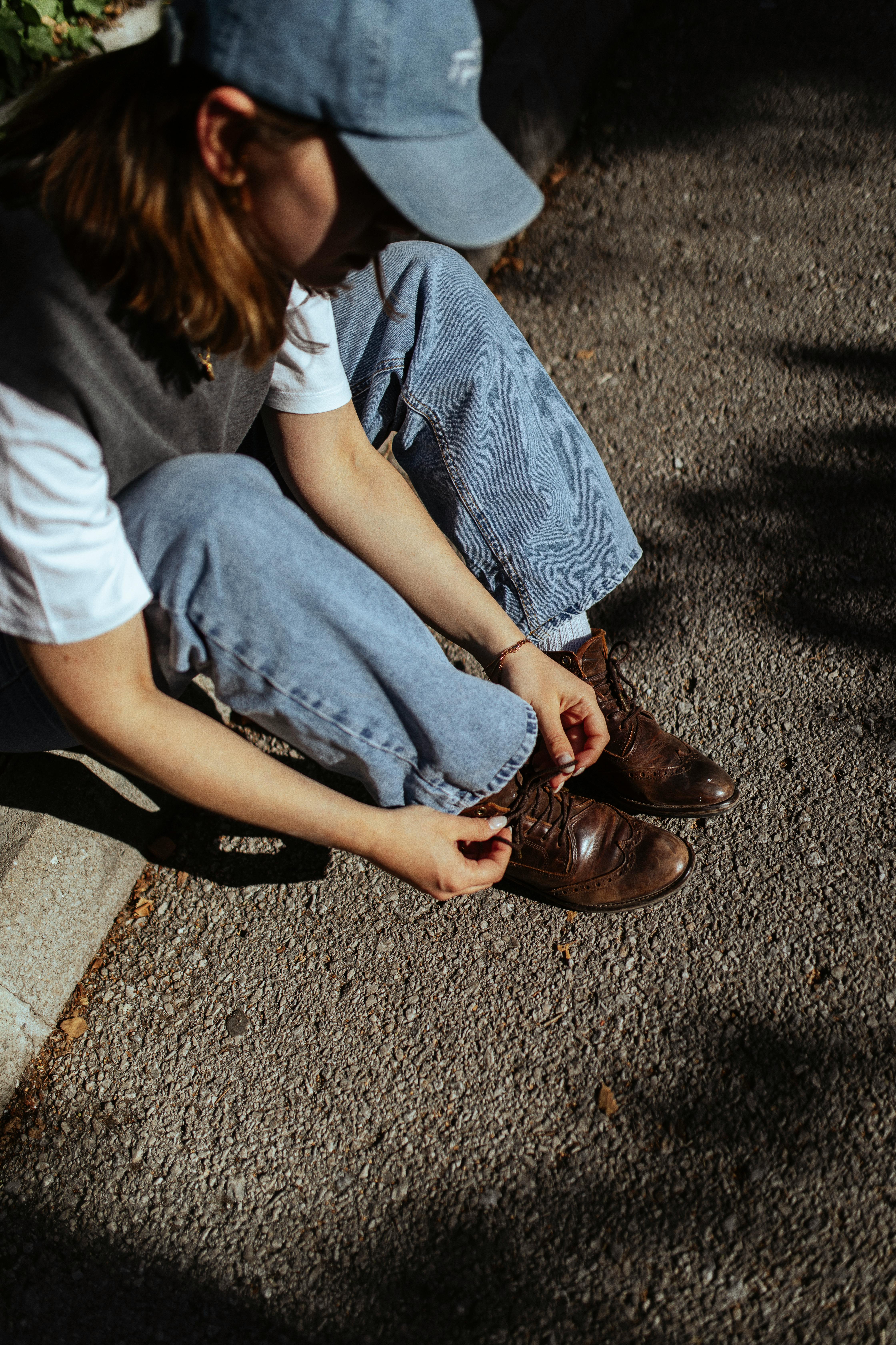Woman Sitting on a Curb and Tying Her Shoe · Free Stock Photo