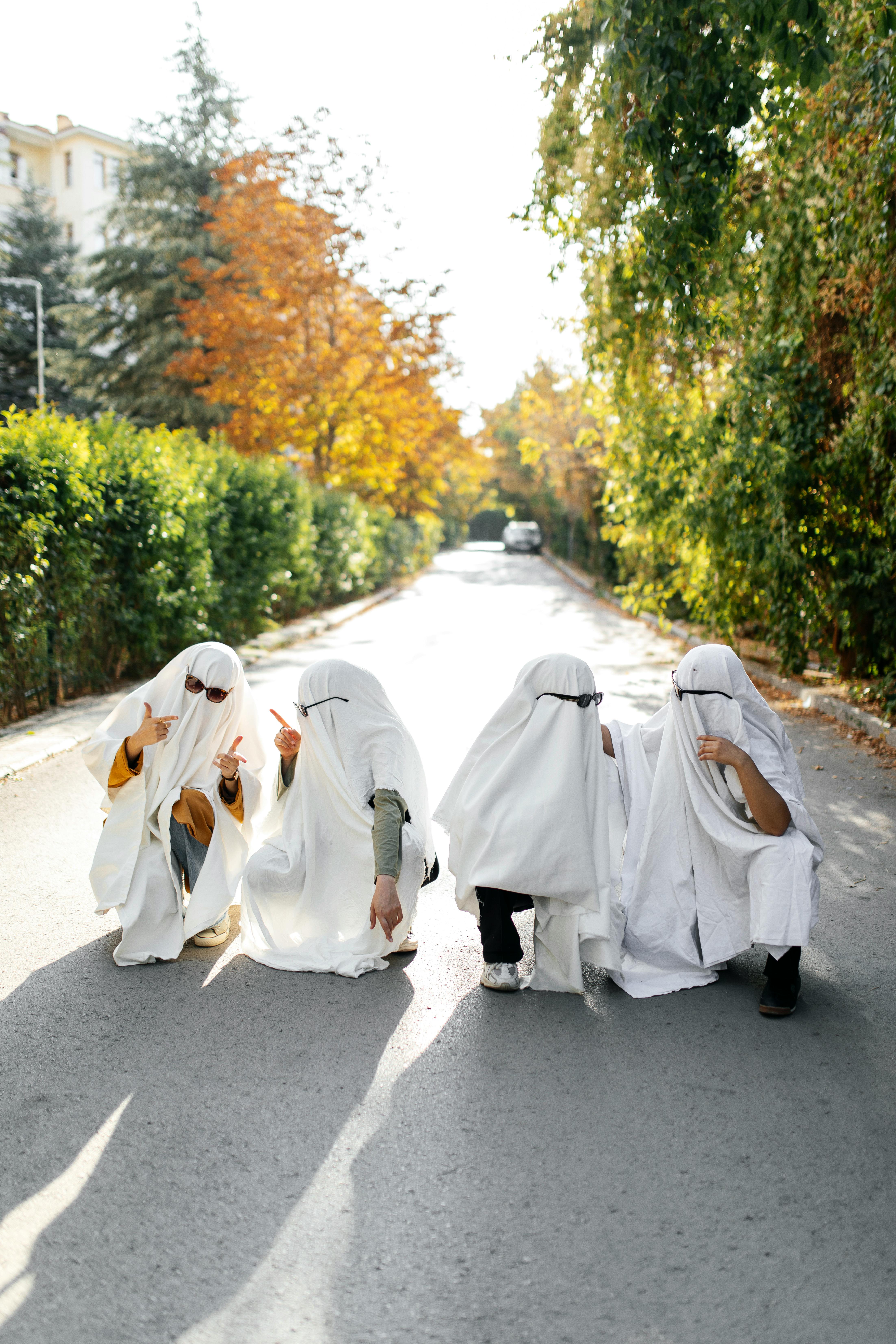 Ghosts in Sunglasses Squatting on Street at Sunset · Free Stock Photo