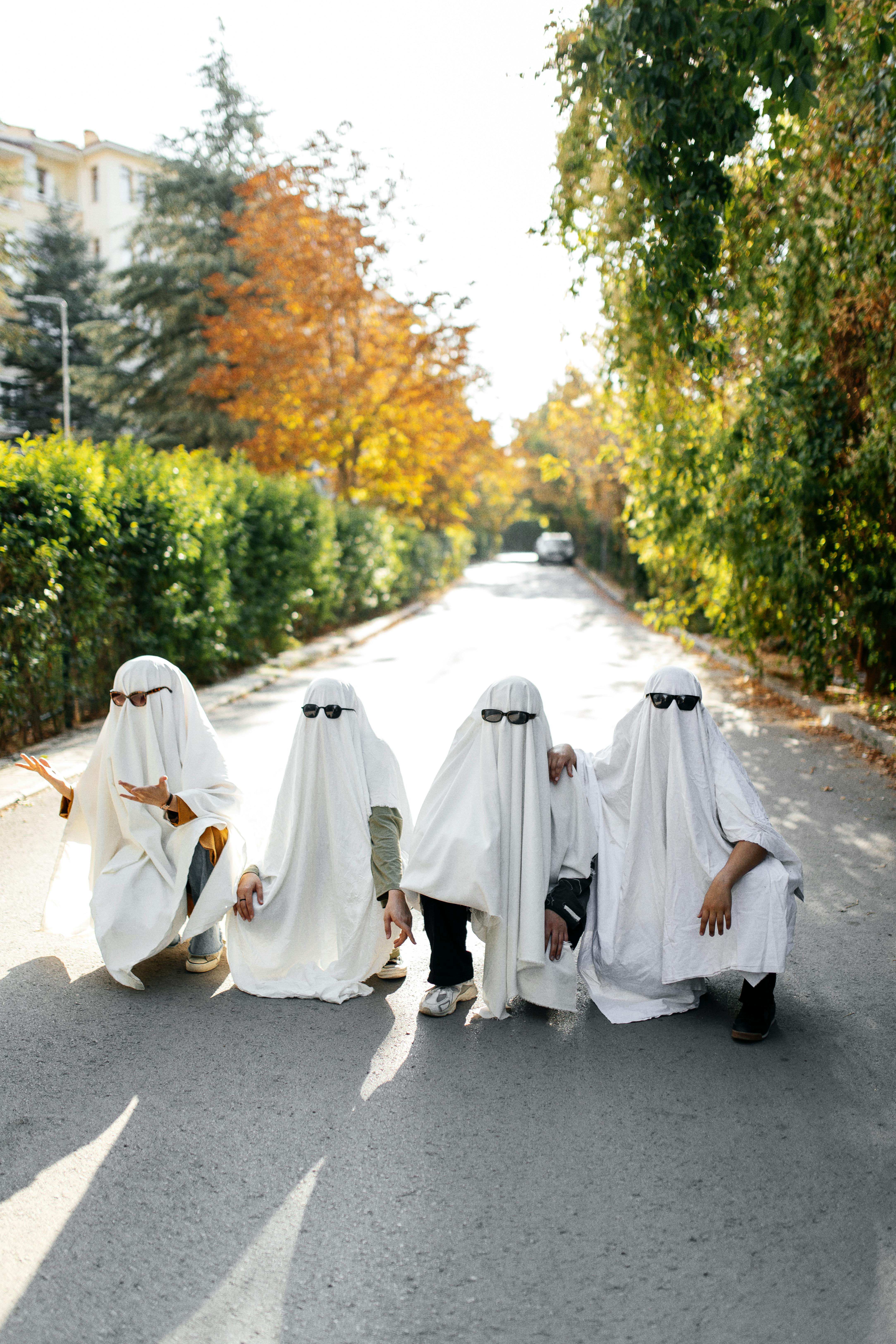 Group of Men Dressed as Ghosts Crouching in the Street · Free Stock Photo