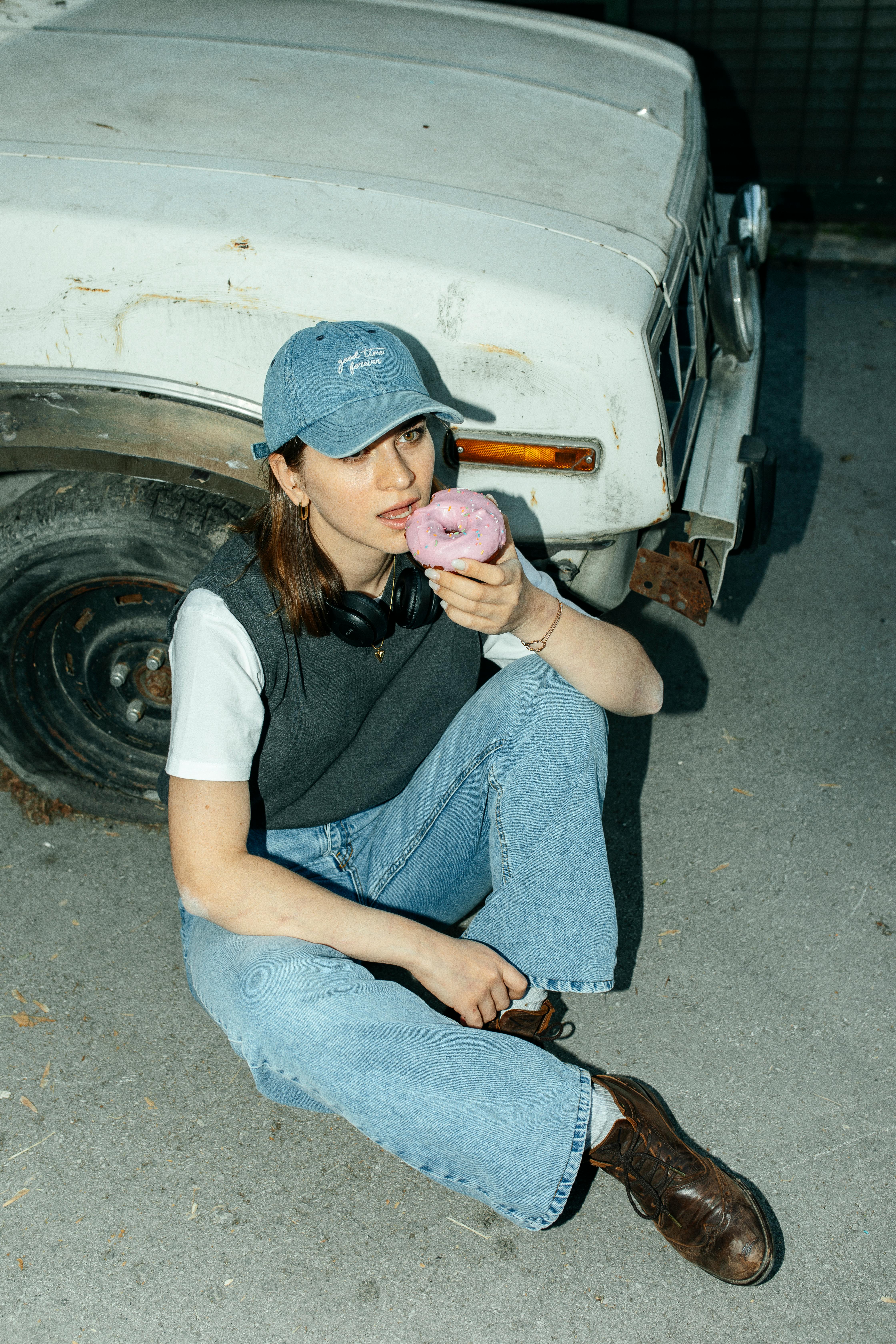 Model in Casual Clothes Eating a Glazed Donut while Sitting on the ...