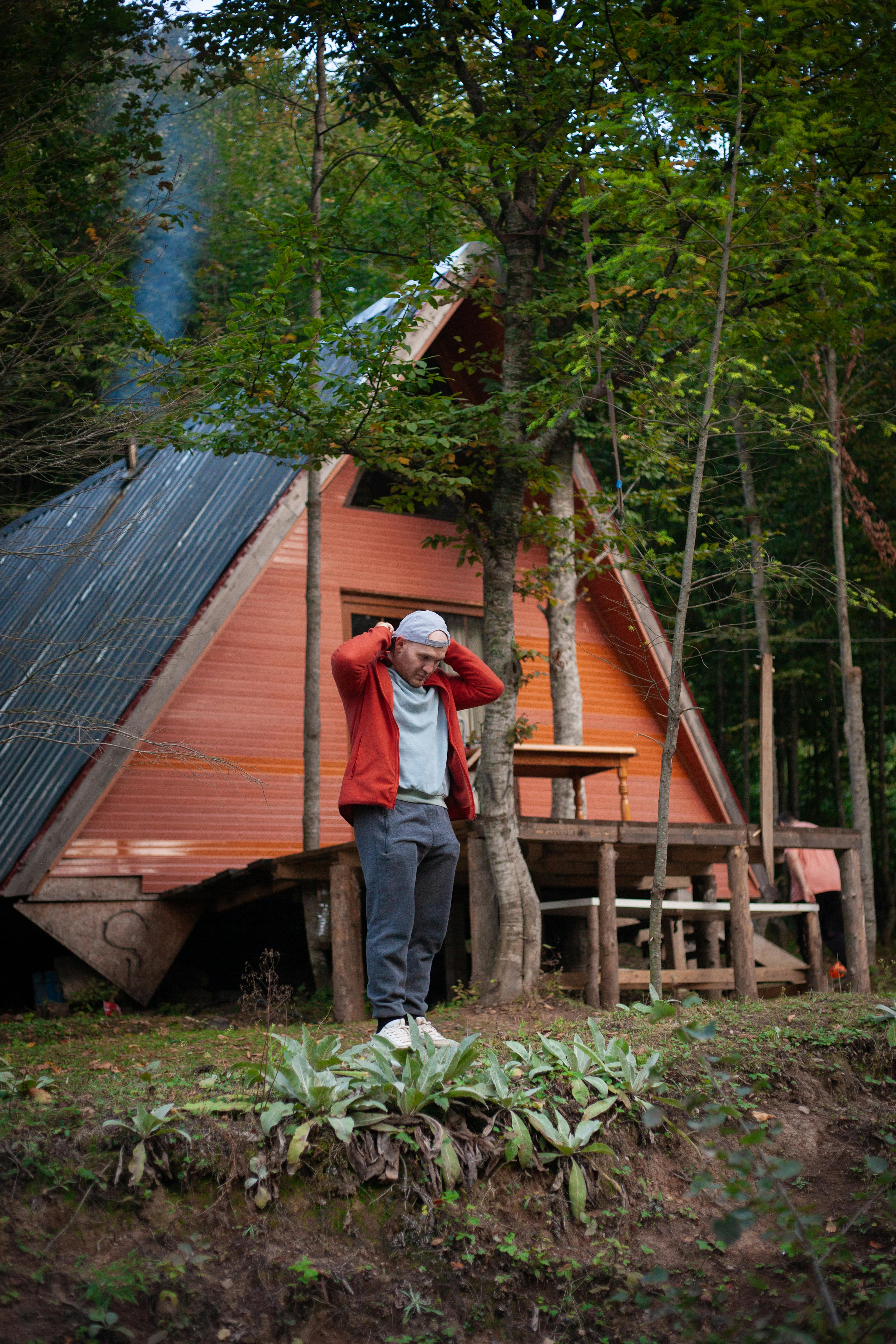 Man by Wooden Hut in Forest · Free Stock Photo