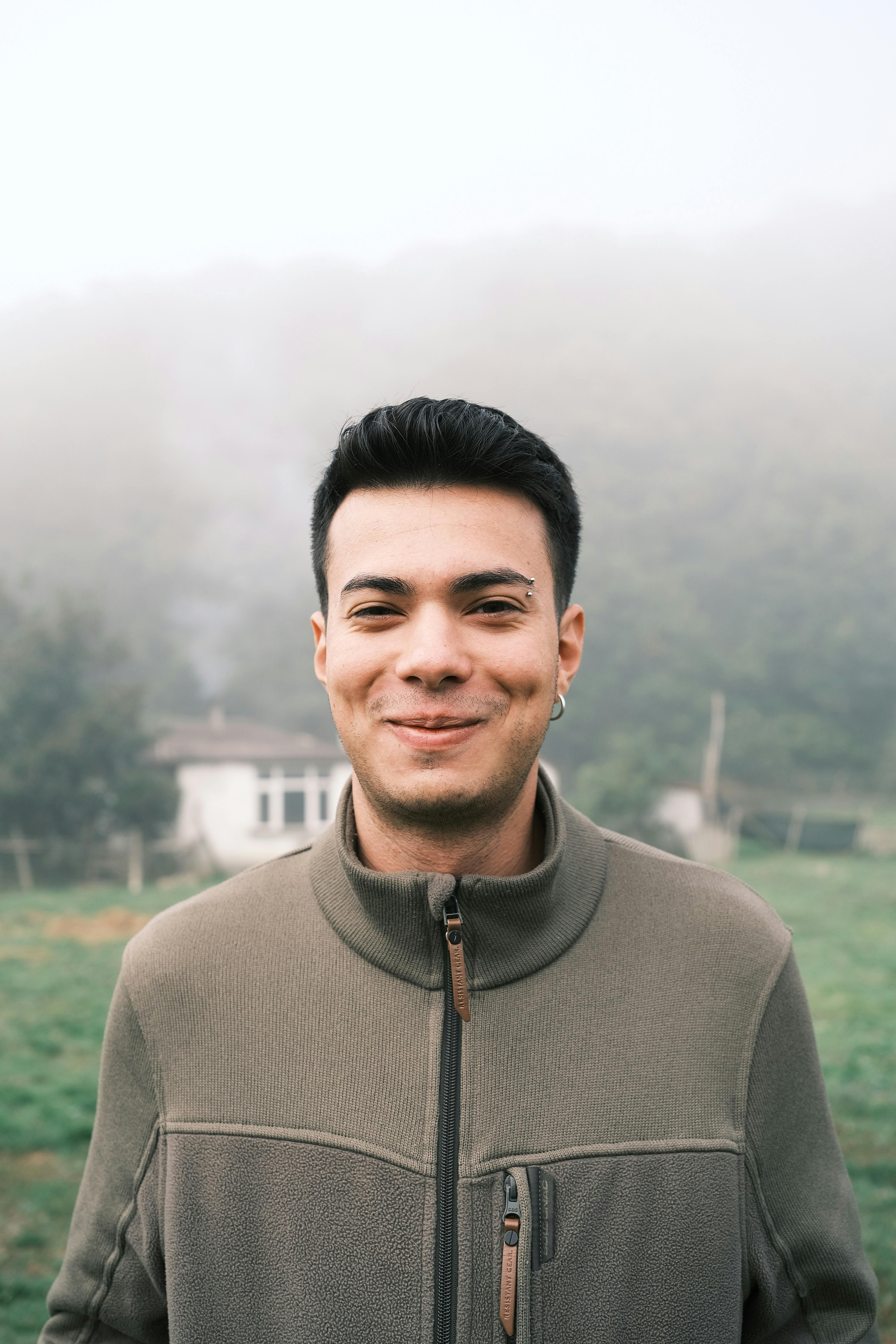 Photo of a Young Man Smiling in Misty Landscape · Free Stock Photo
