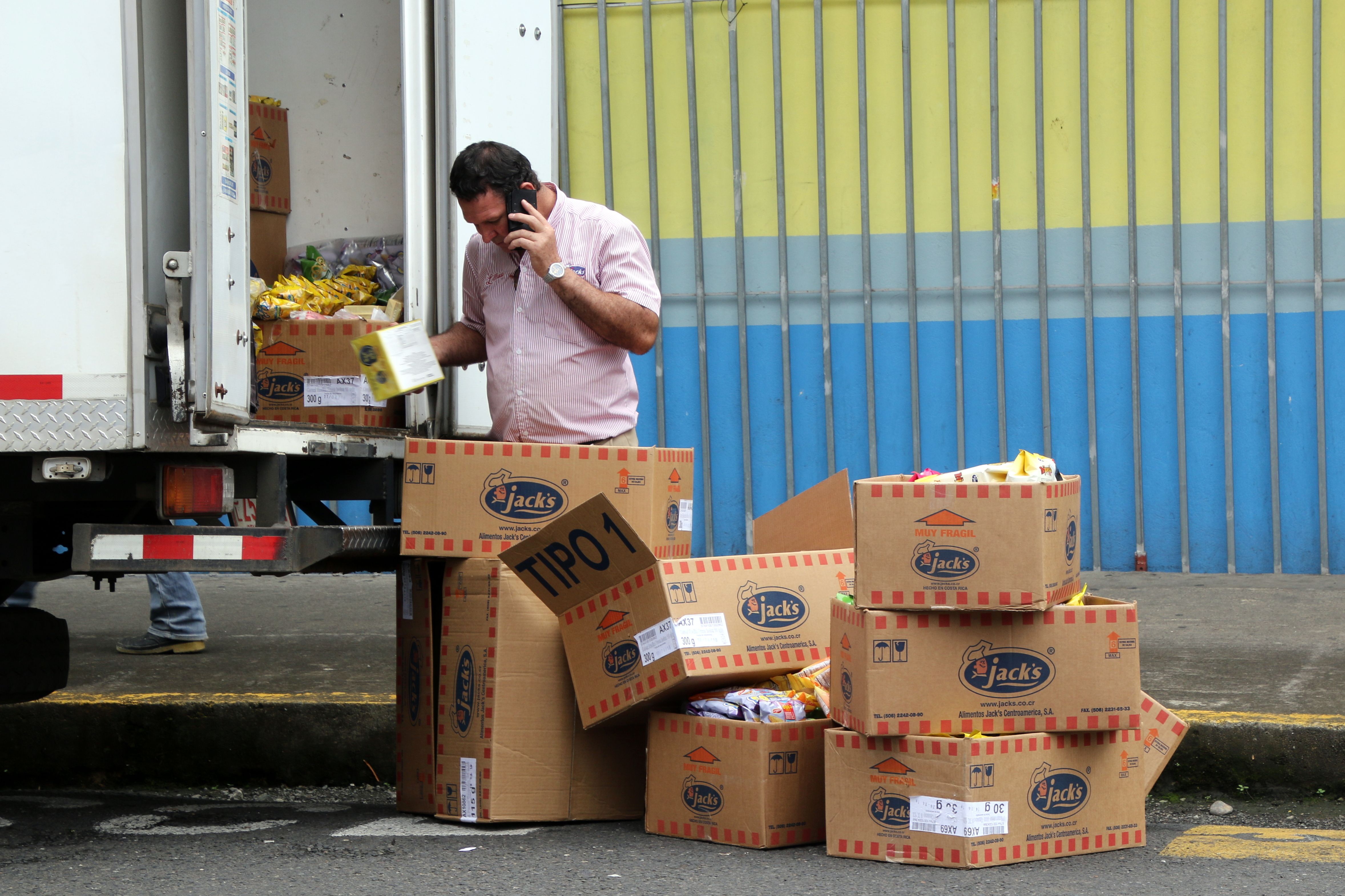 Man in Shirt Talking on Phone by Boxes near Truck · Free Stock Photo
