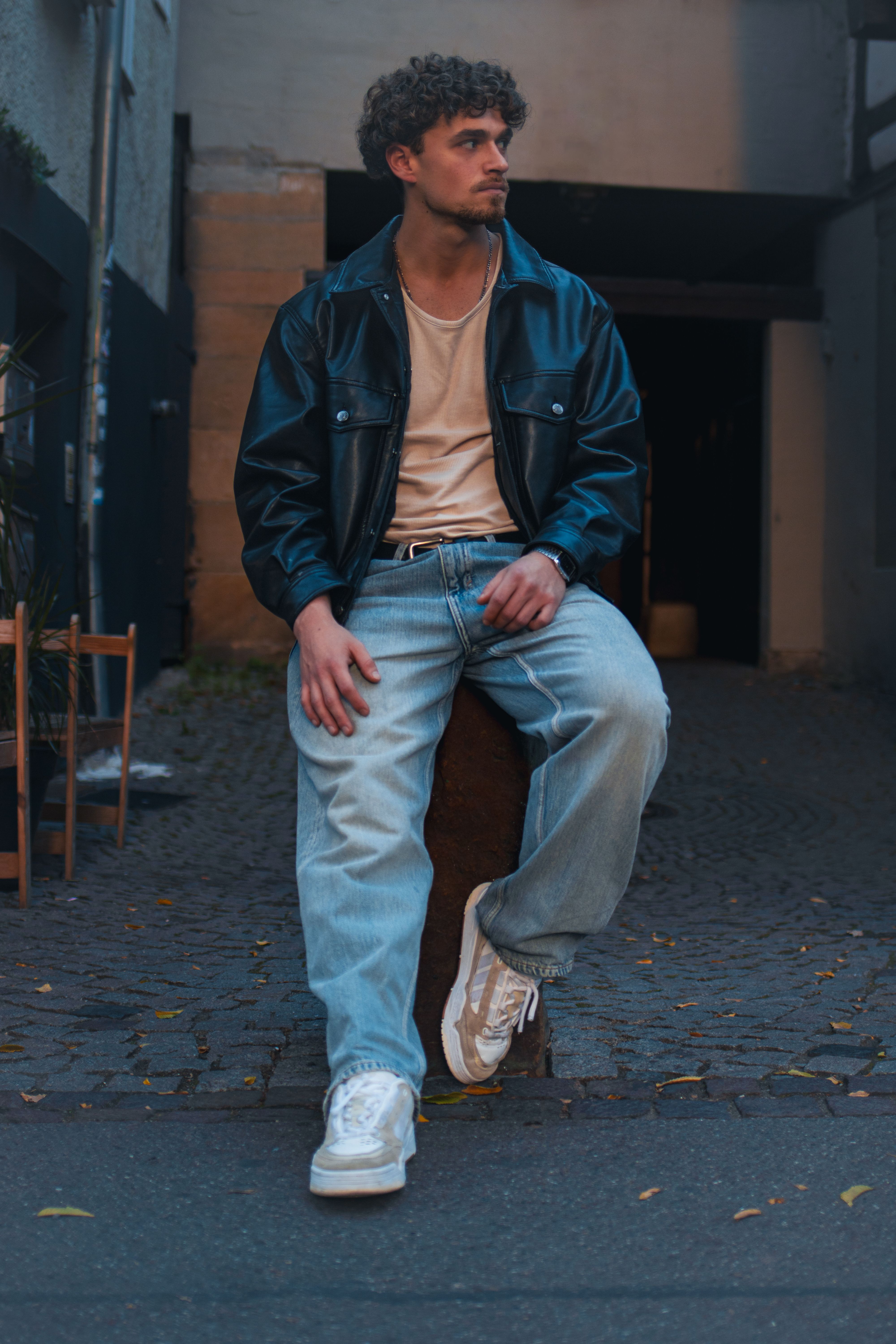 Man in Leather Jacket Sitting on Post by Street · Free Stock Photo