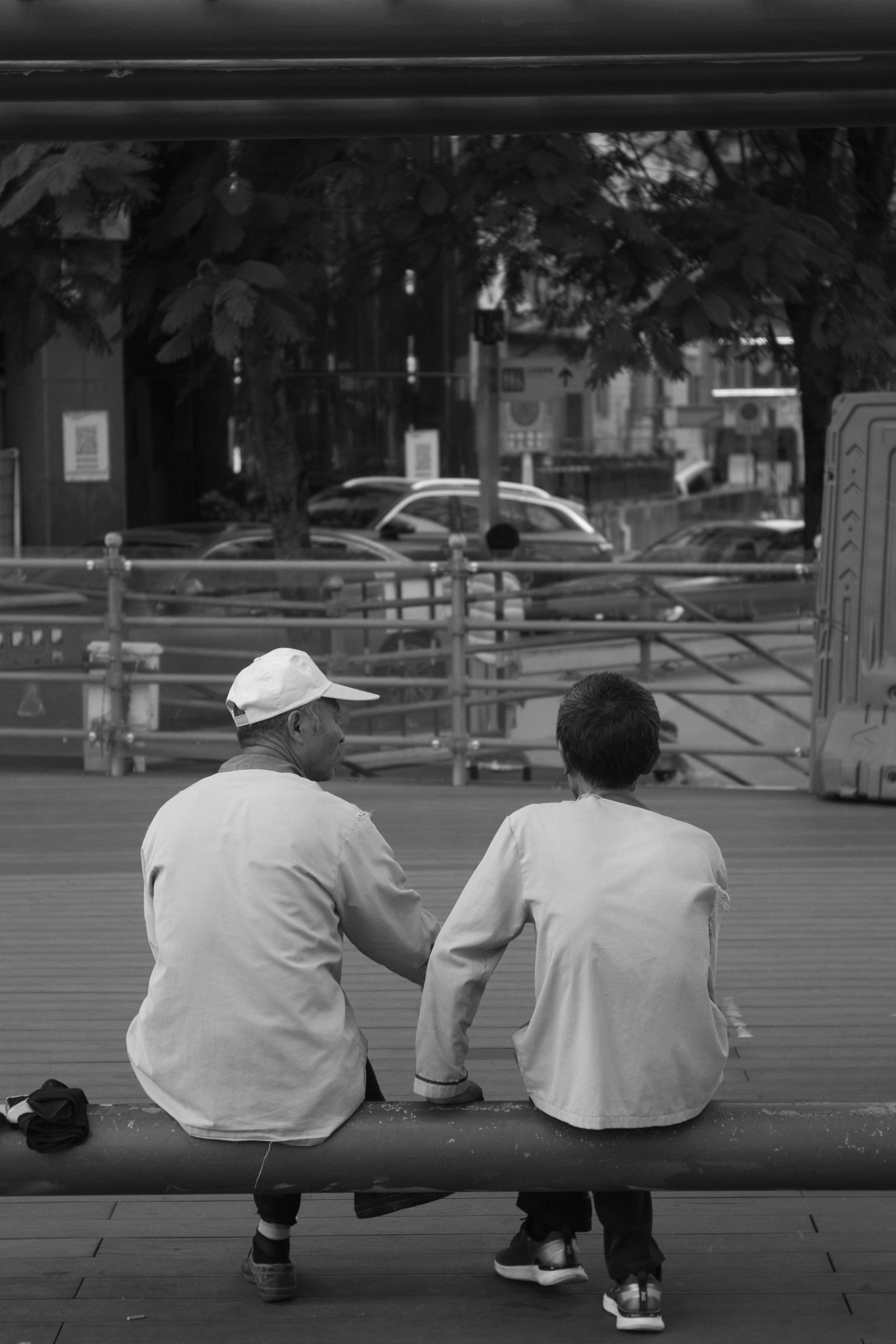 Back View of Two People Sitting on a Bench in City · Free Stock Photo