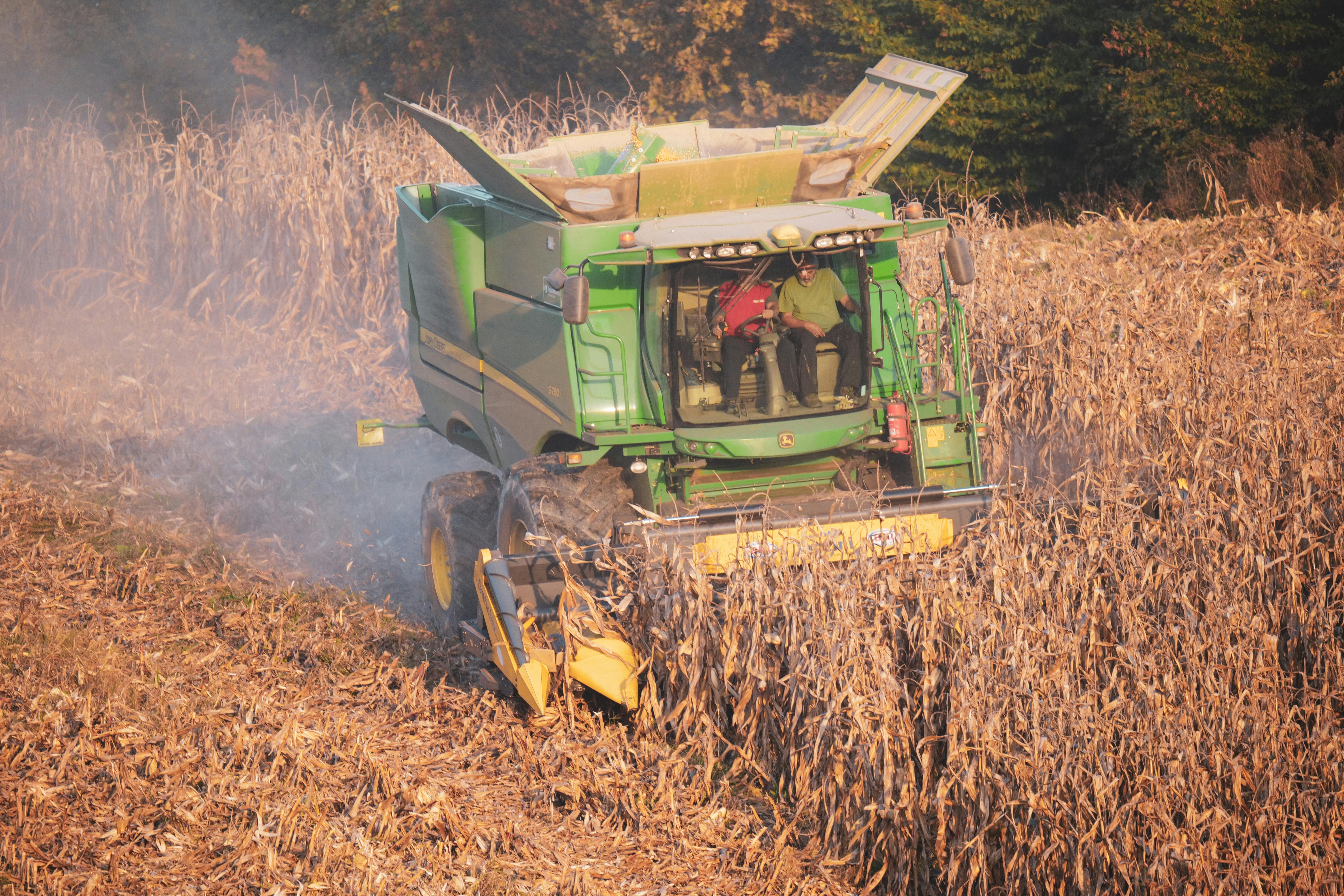 Two Men in a Green Harvester Cutting Corn on a Field · Free Stock Photo