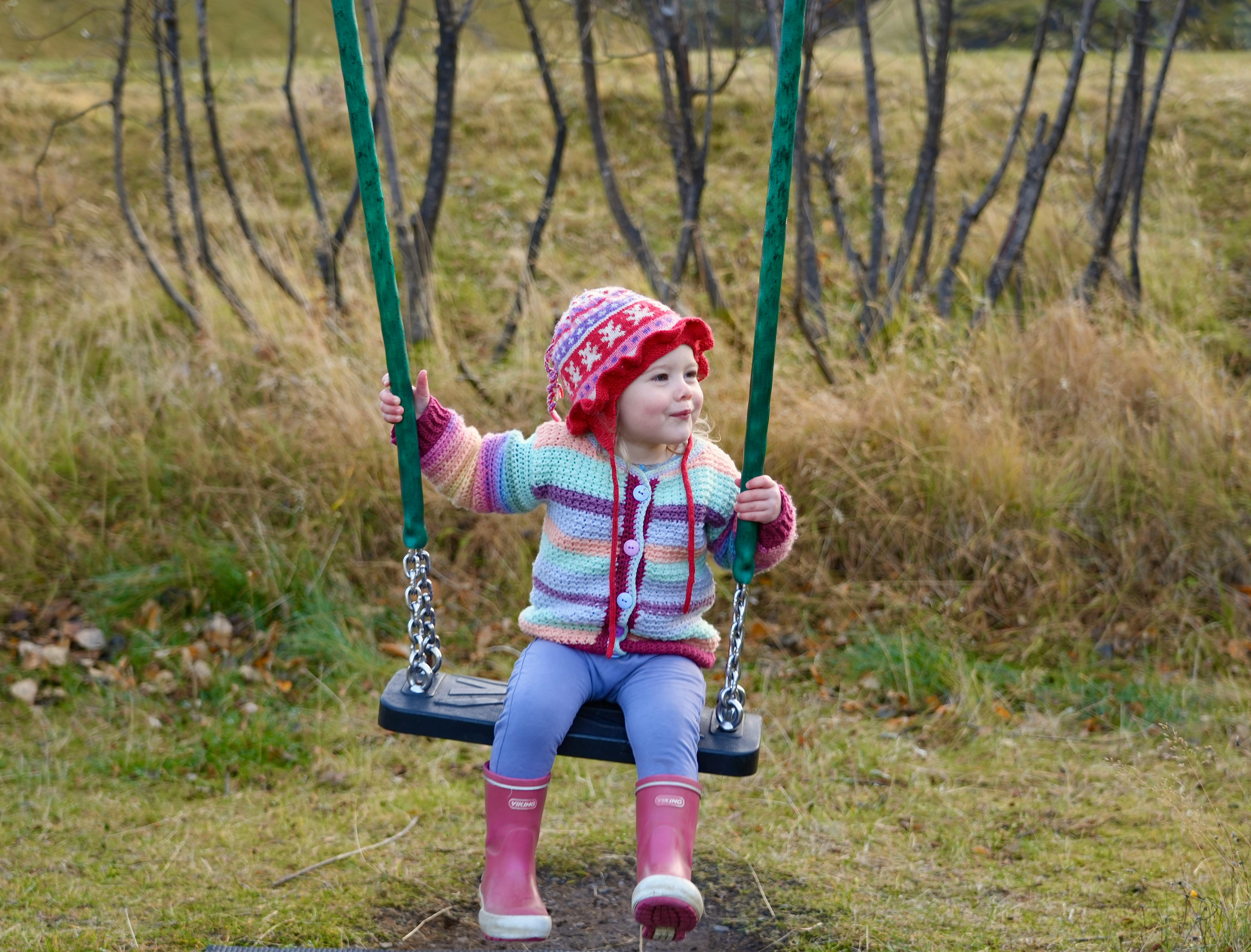 A small child on a swing in the grass · Free Stock Photo