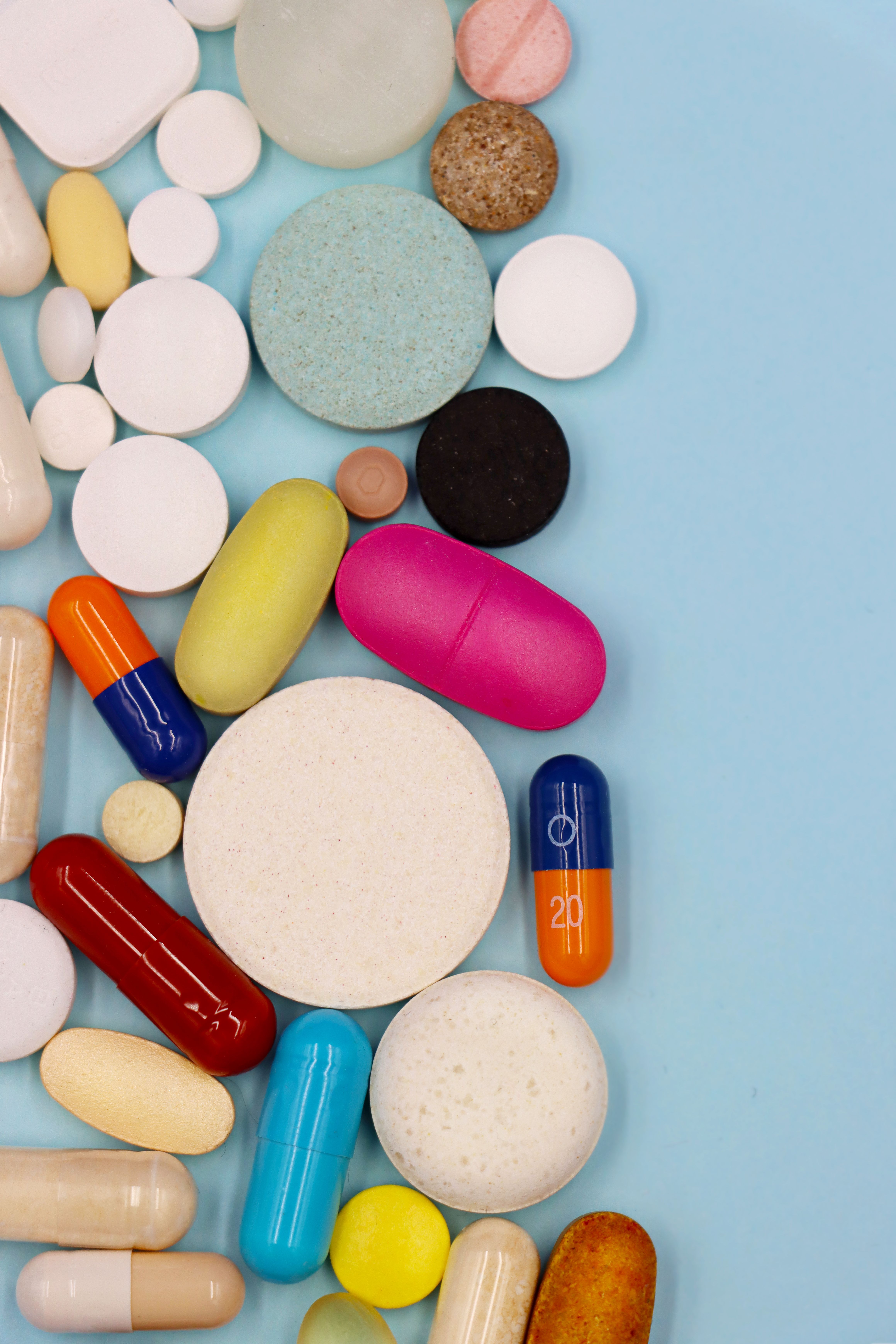Mixed Medical Pills on a Blue Background · Free Stock Photo