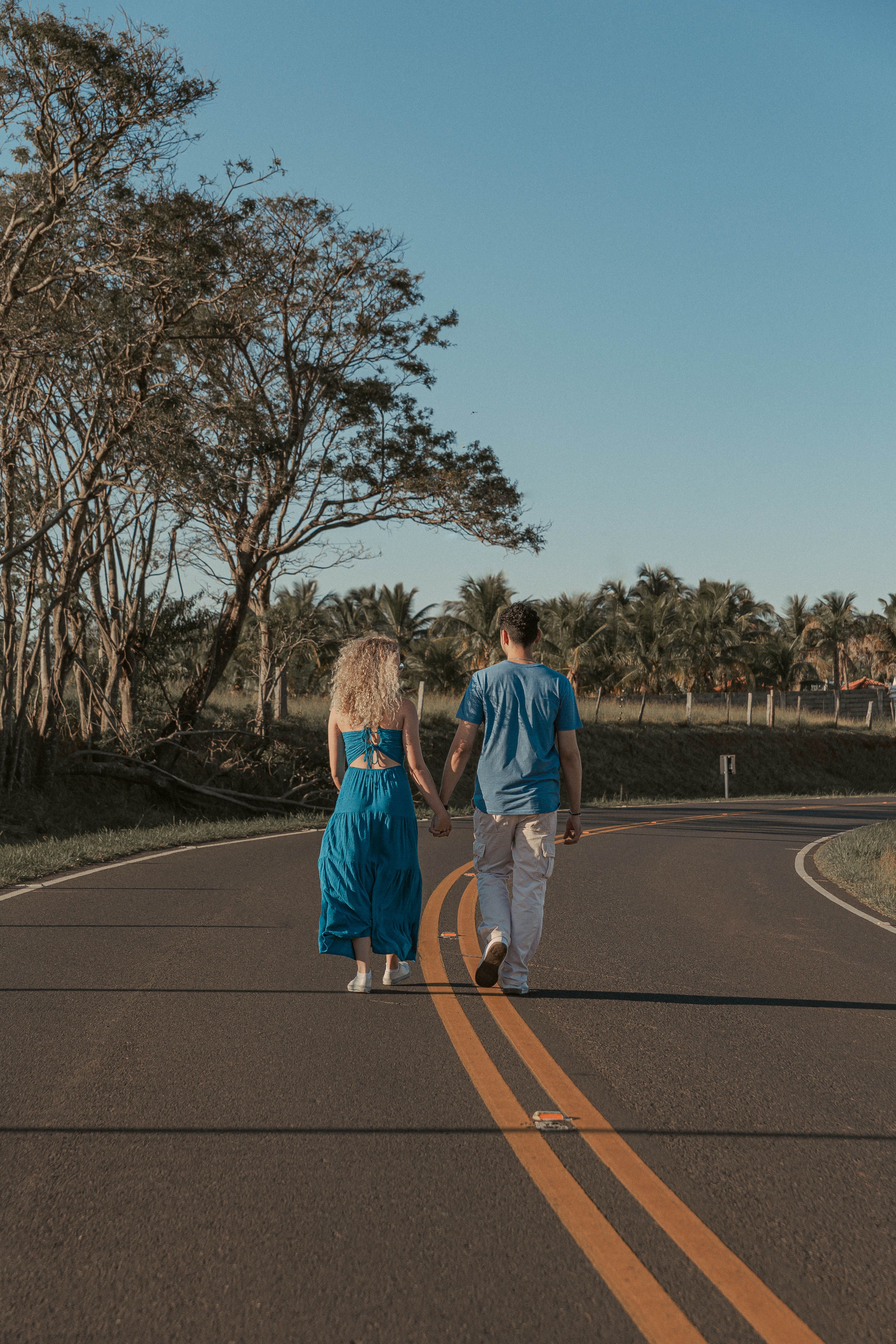 Man and Woman Walking along Road Holding Hands · Free Stock Photo