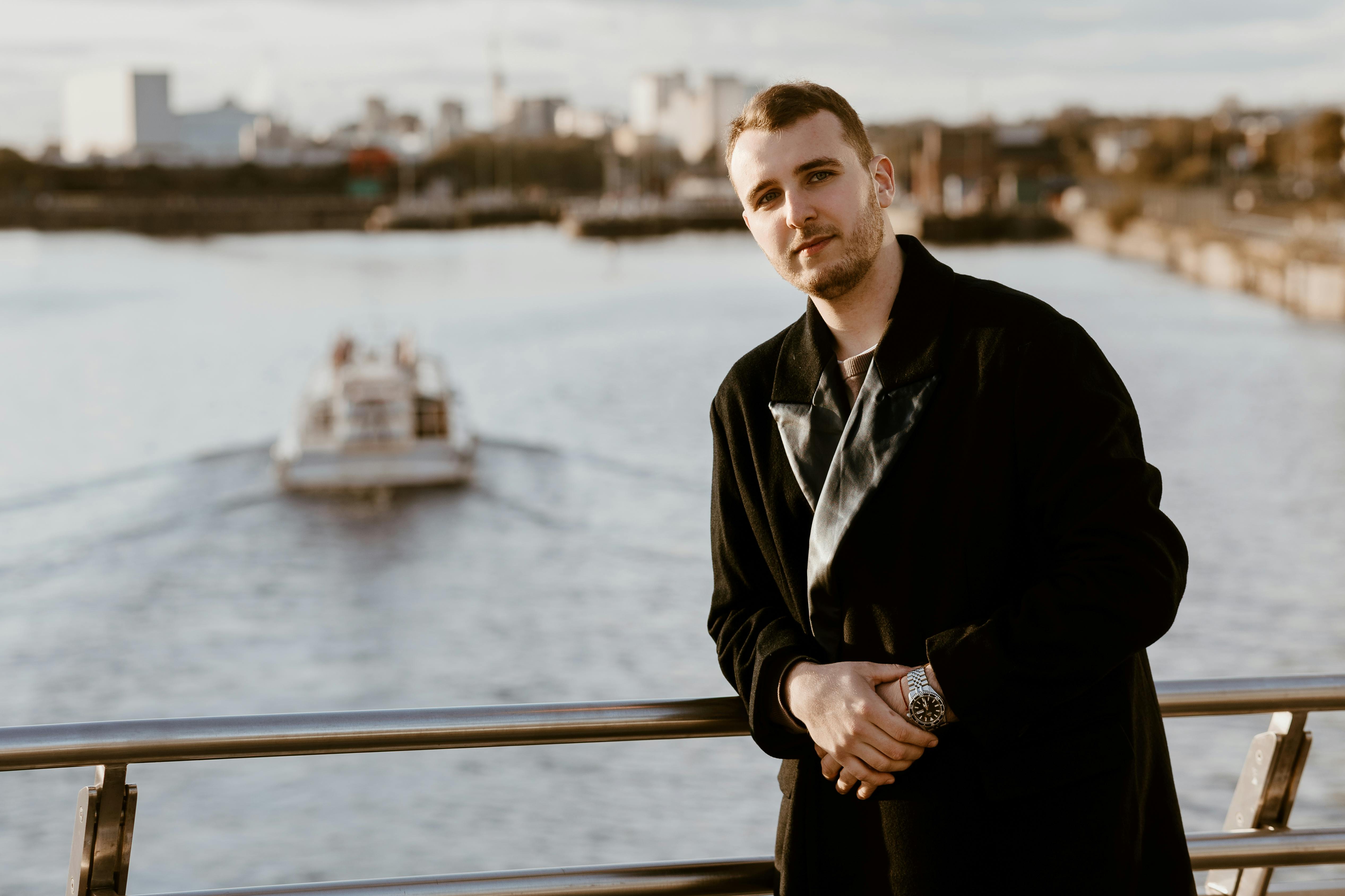 A man in a black coat standing on a bridge · Free Stock Photo