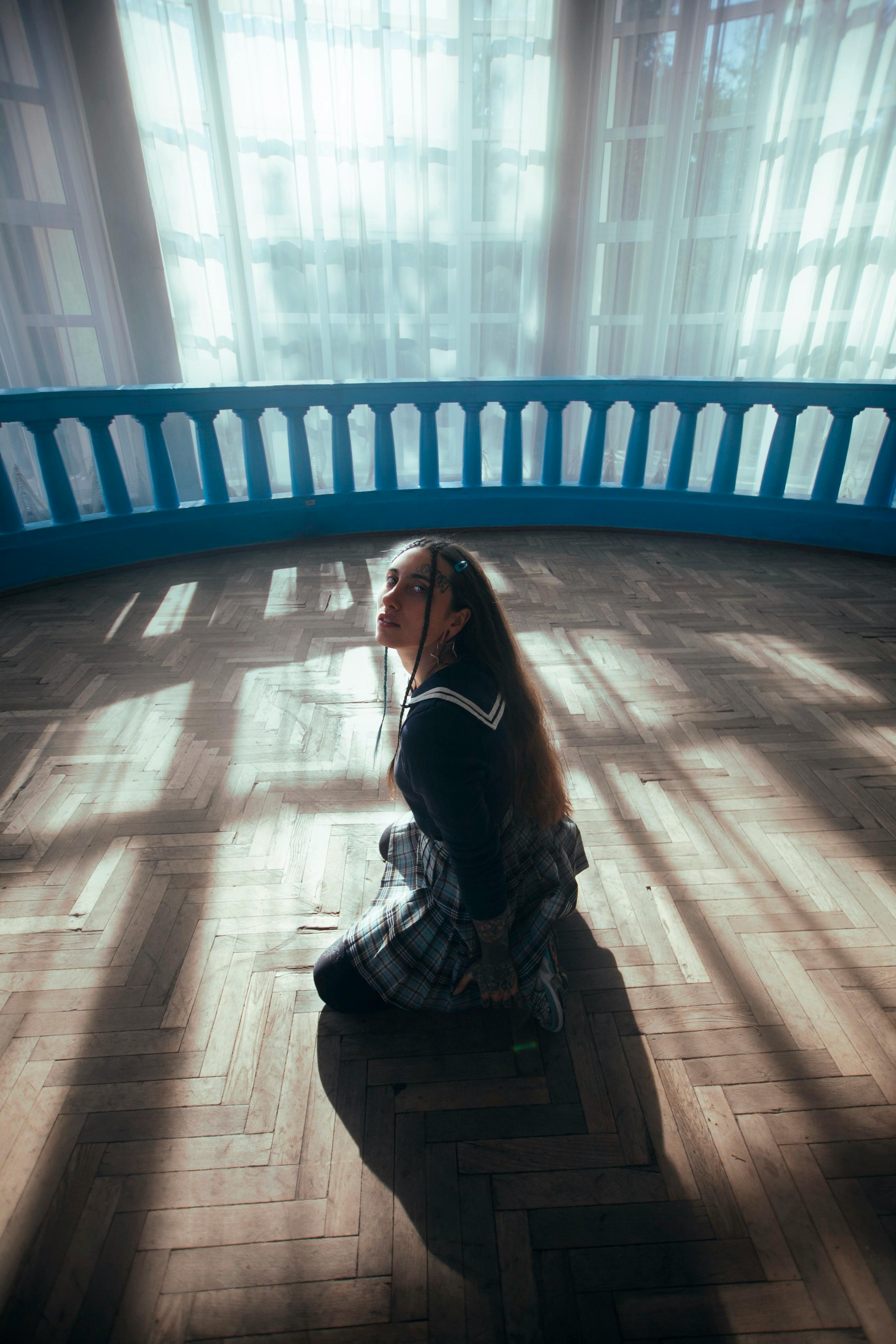 Young Woman in a Plaid Skirt Crouching on the Floor · Free Stock Photo