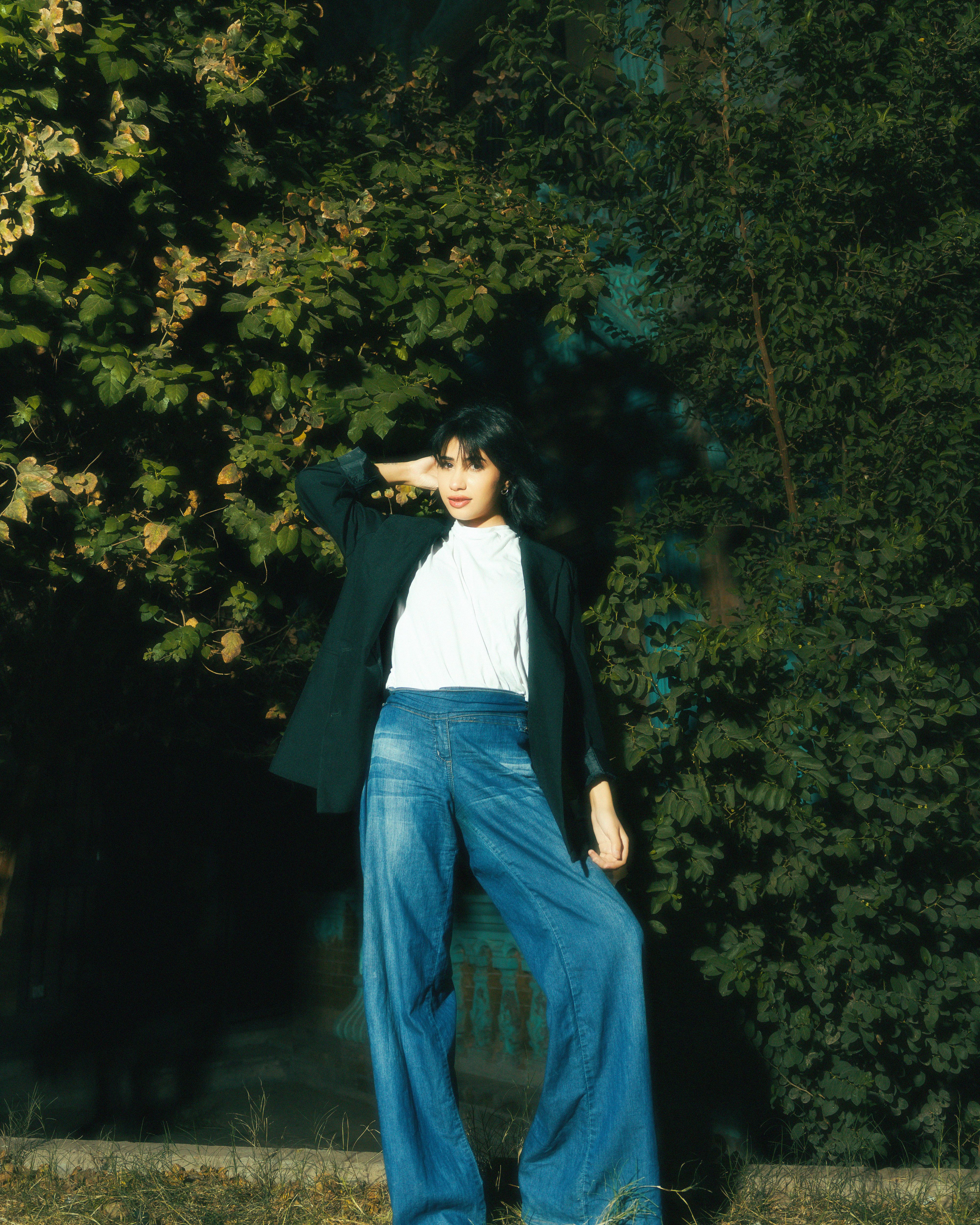 Woman in Loose Jeans Standing by Trees · Free Stock Photo
