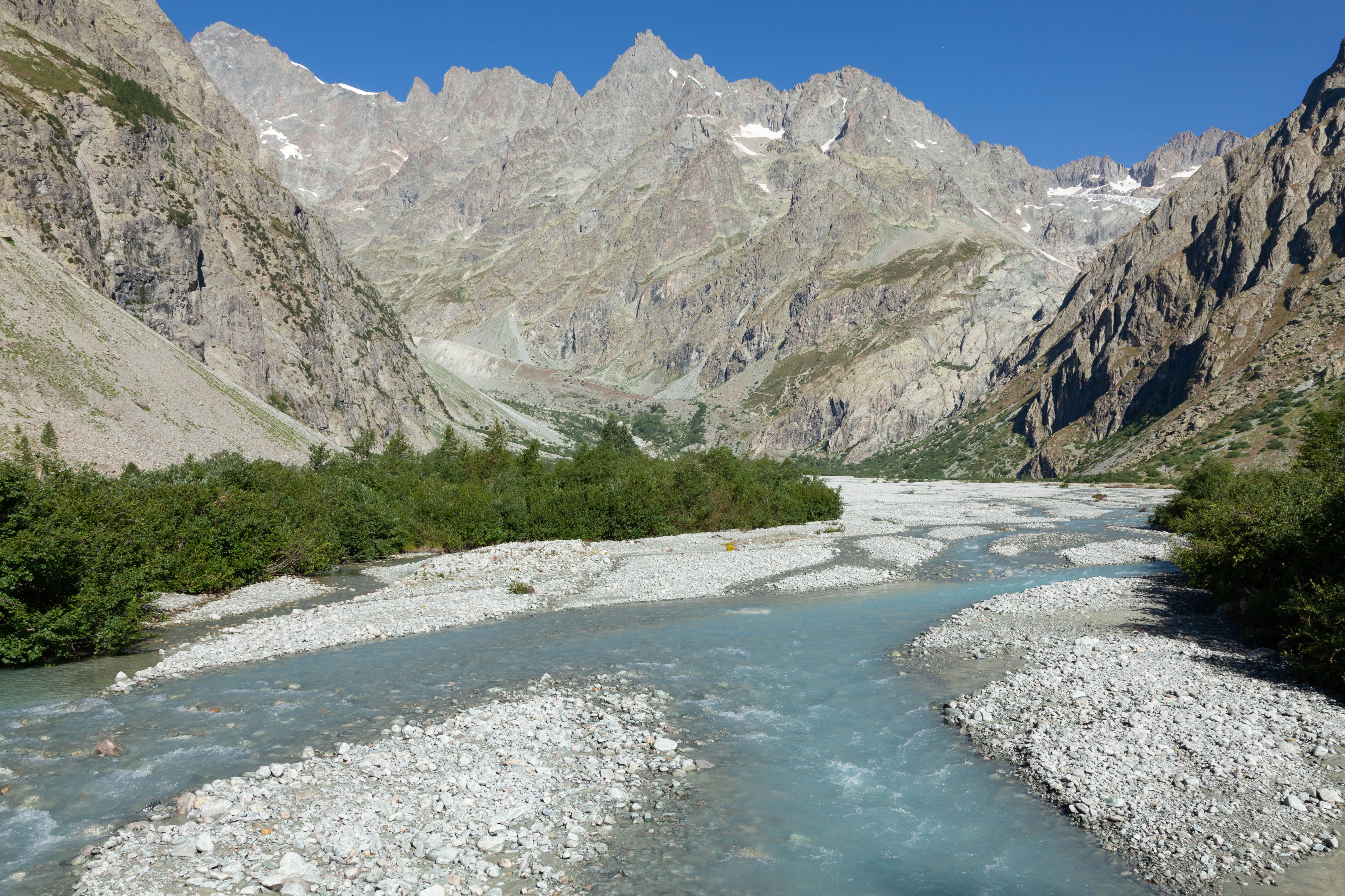 A river flowing through a valley with mountains in the background ...
